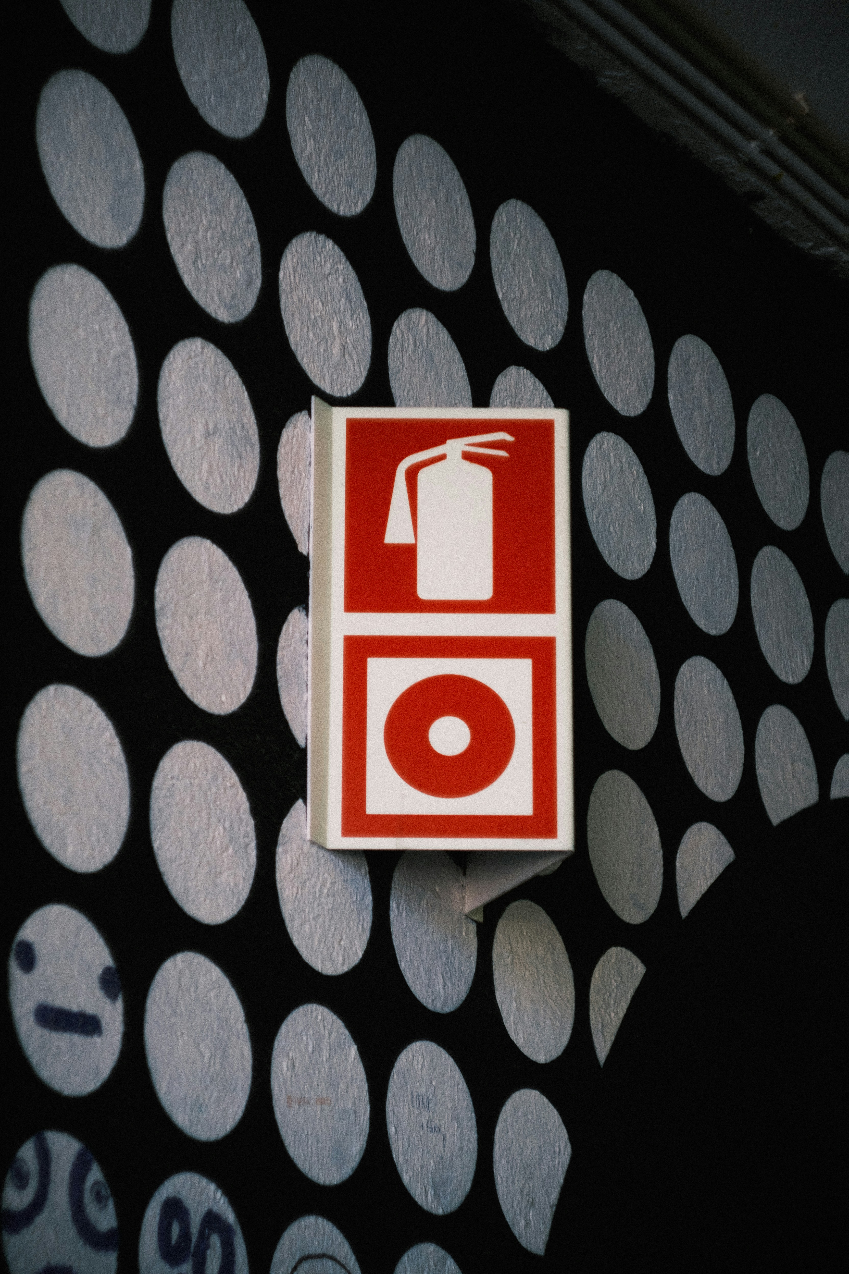 Red fire extinguisher sign resting on a dotted black wall