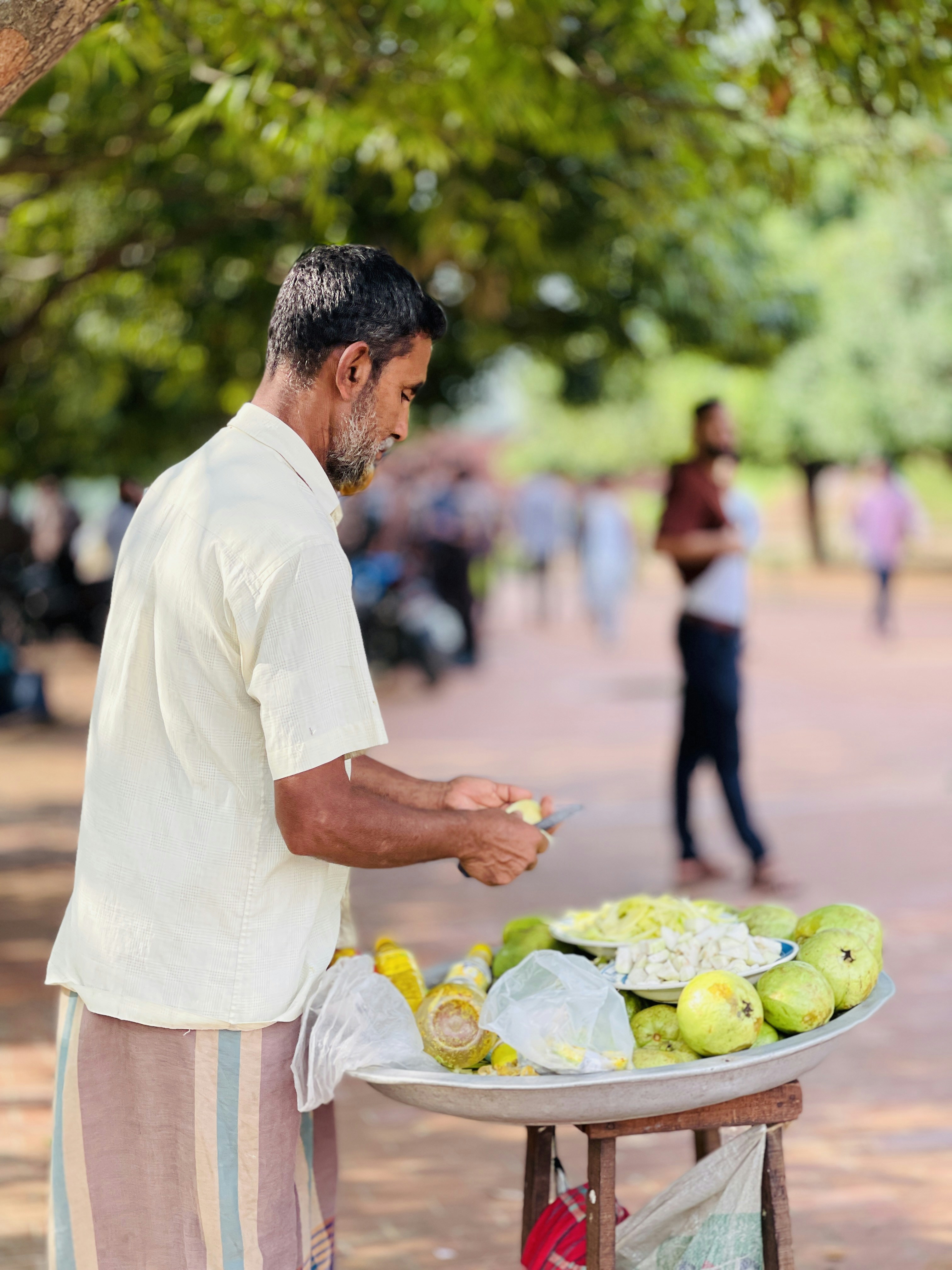 Street Vendor in Focus: Fruit Stand Beneath a Sunlit Canopy
