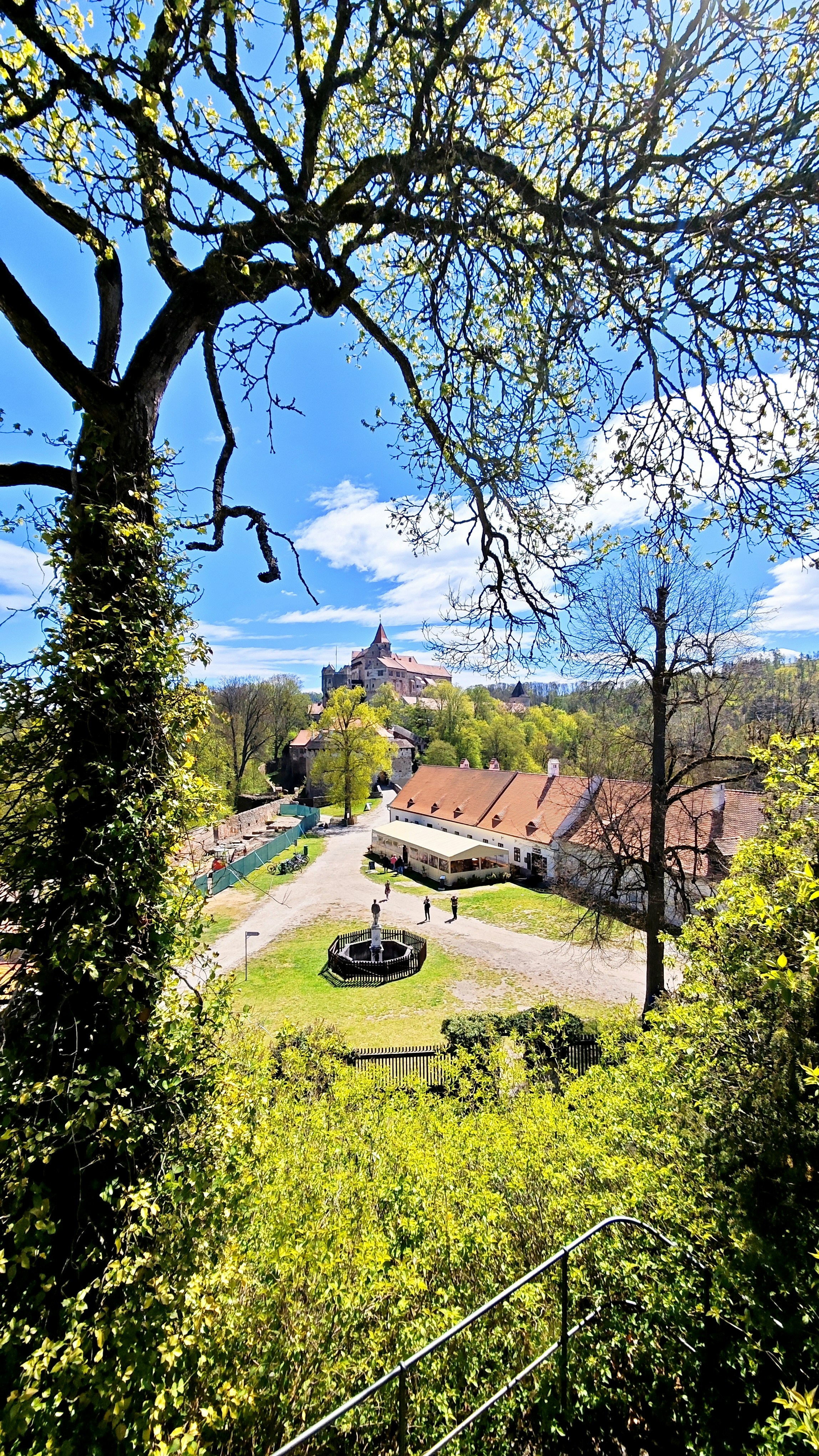 View from the Framing Tree: a sunlit village square under a castle-spired hill