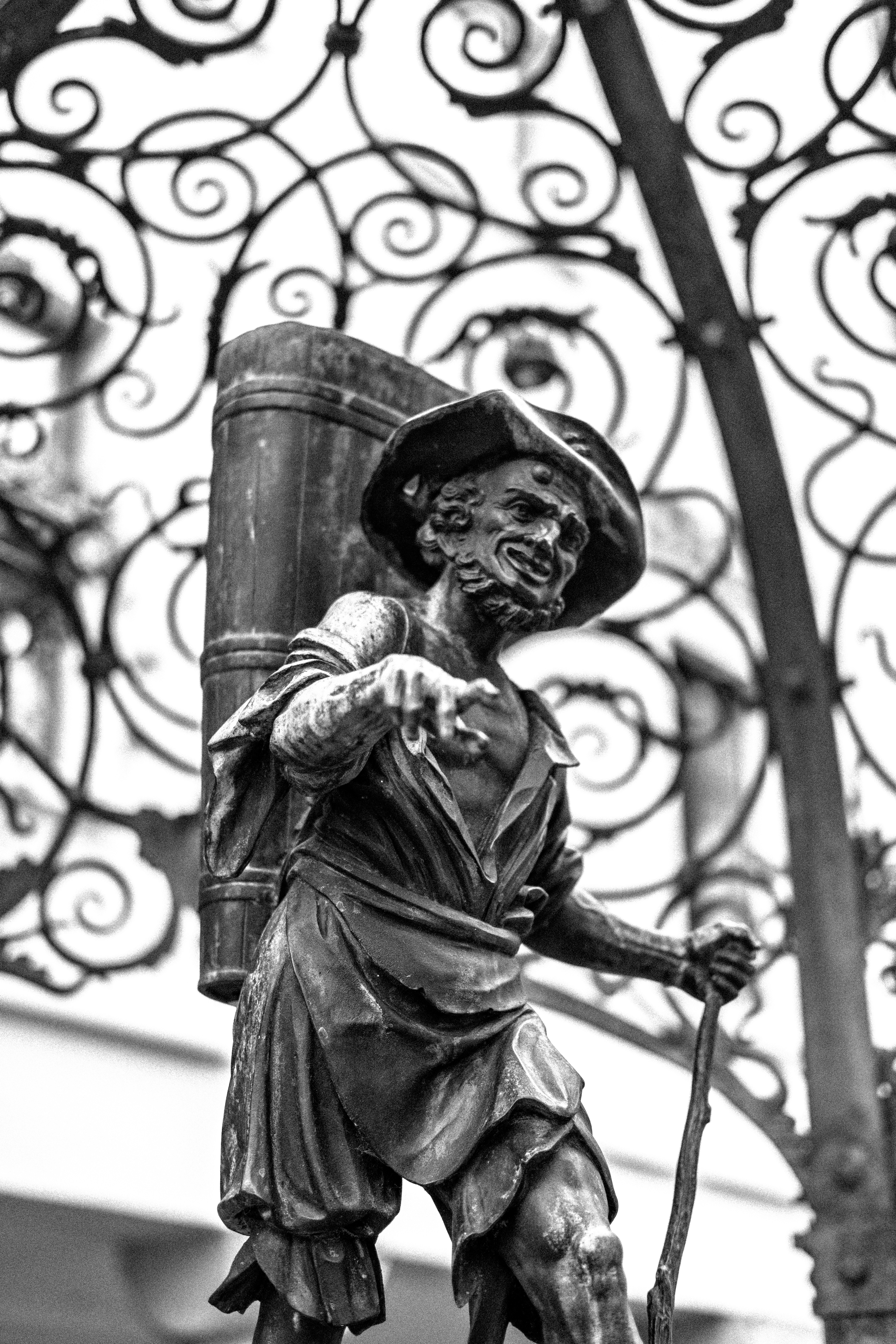 Metalworker of Stone: A Charismatic Gardener Figure Against Ornate Ironwork