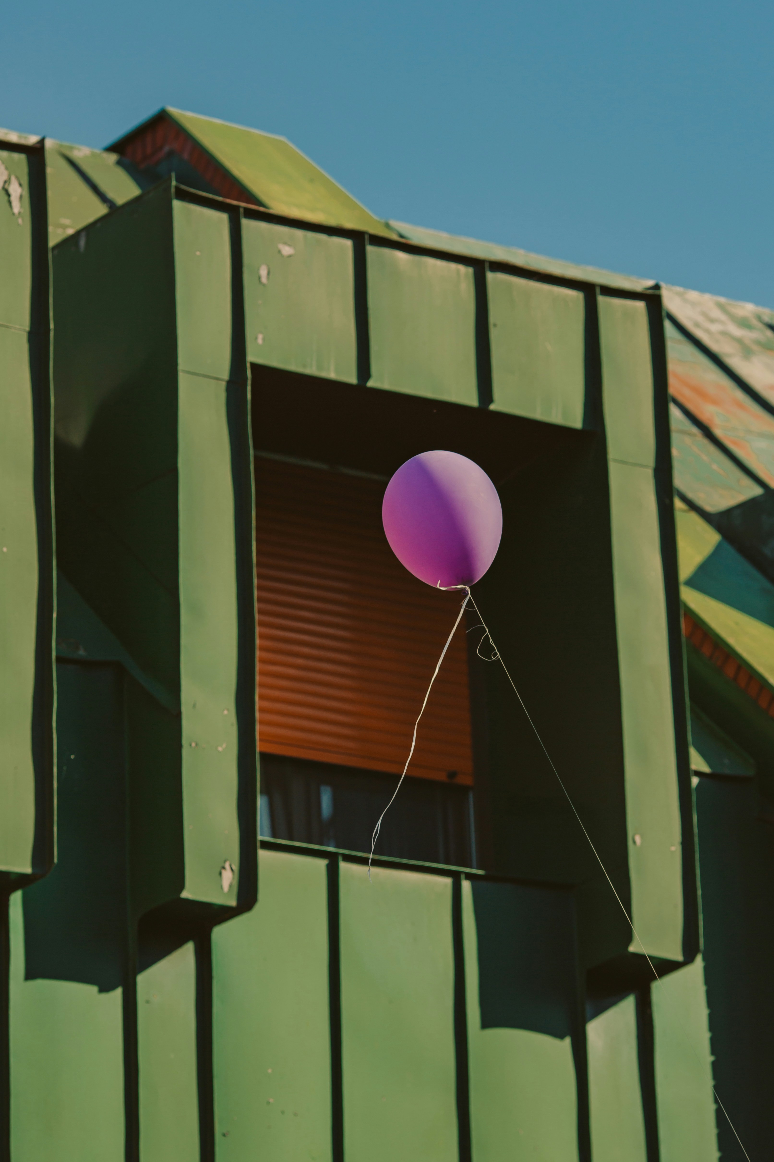 Purple Balloon Adrift from a Green Facade