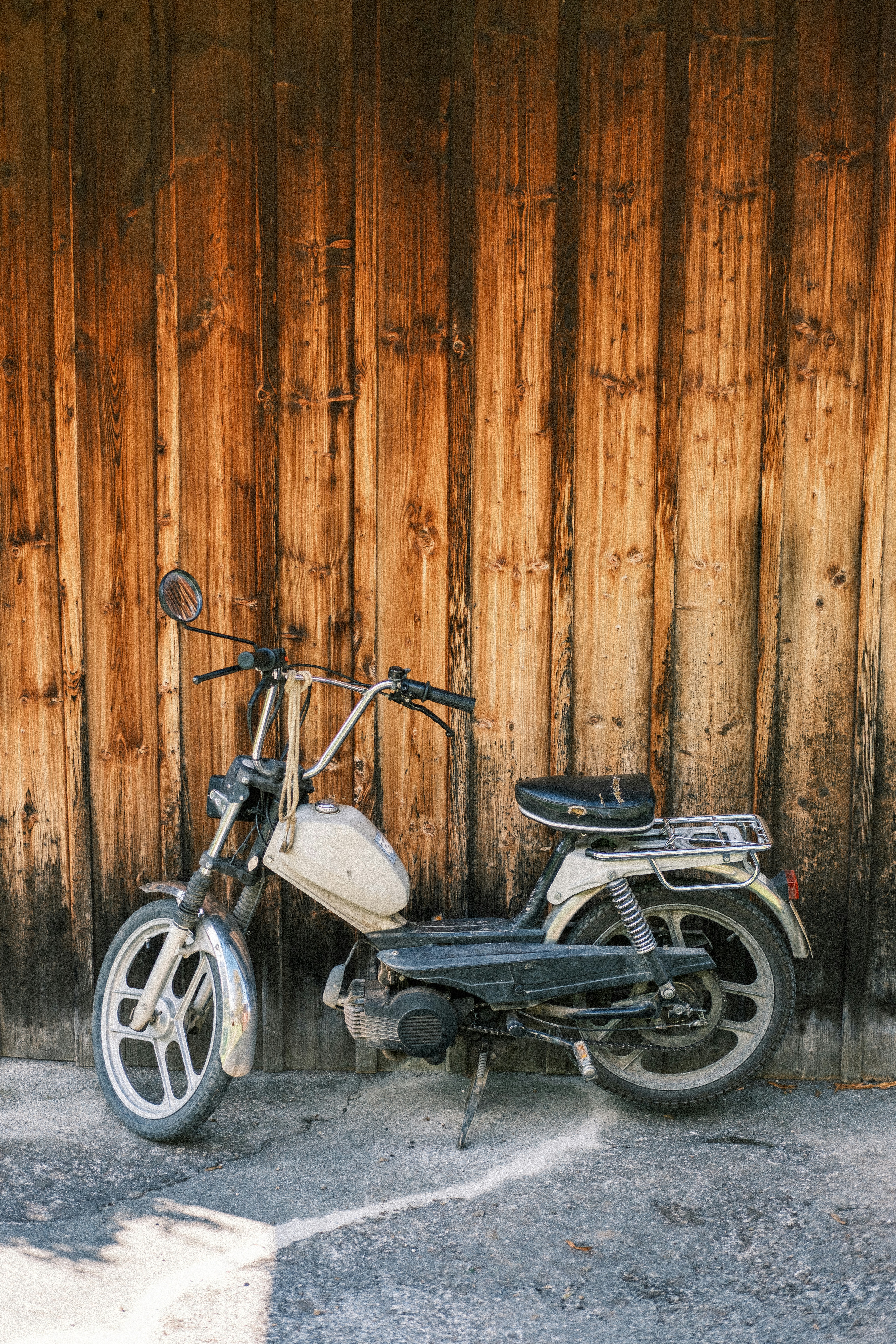Resting relic: a weathered moped leaning against a wooden wall