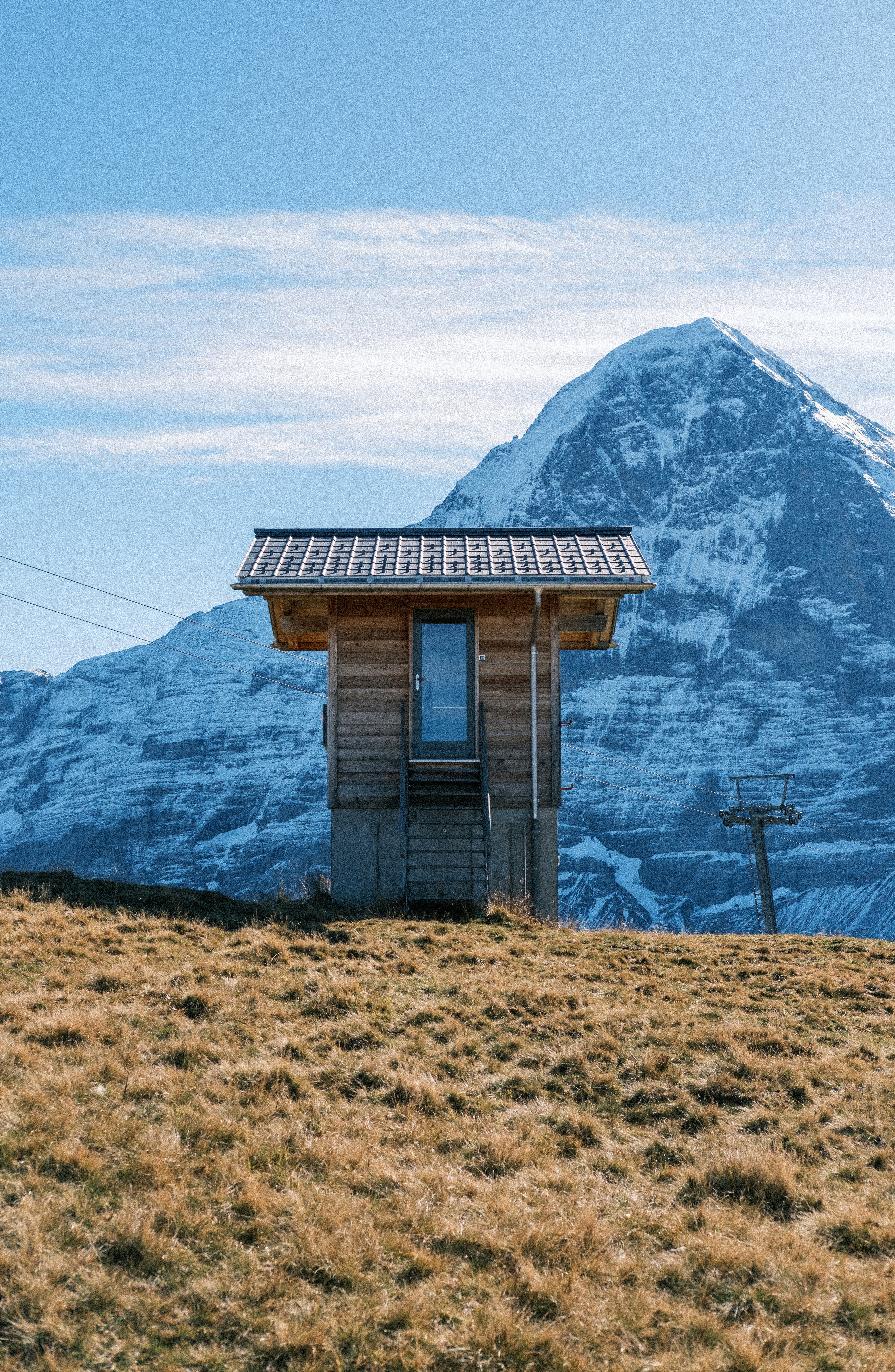 Highland Custodian: A Wooden Lookout Nest Amid Snowy Peaks