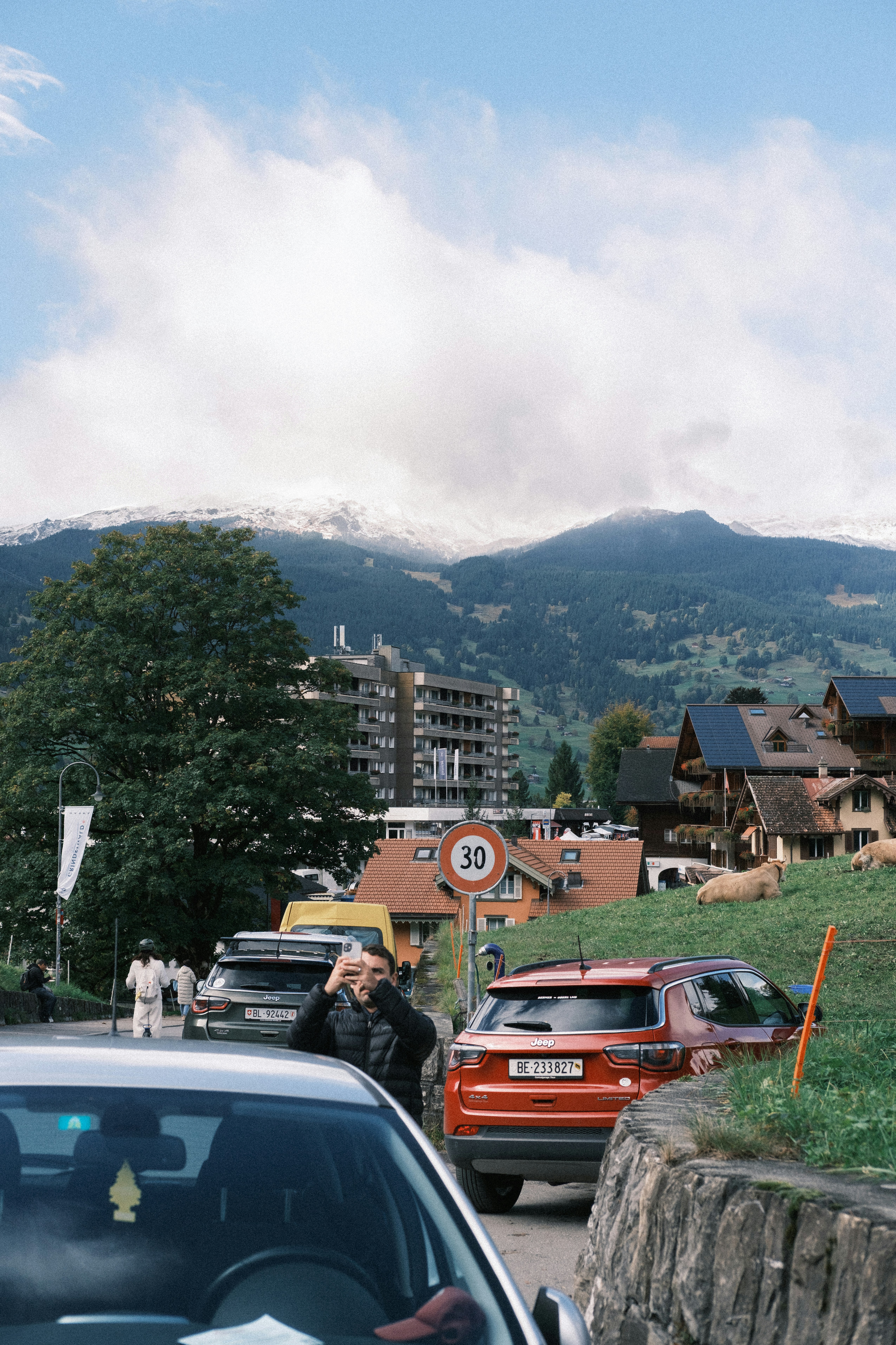 Village Street Portrait: Cars, Signage, and a Man Capturing the Moment