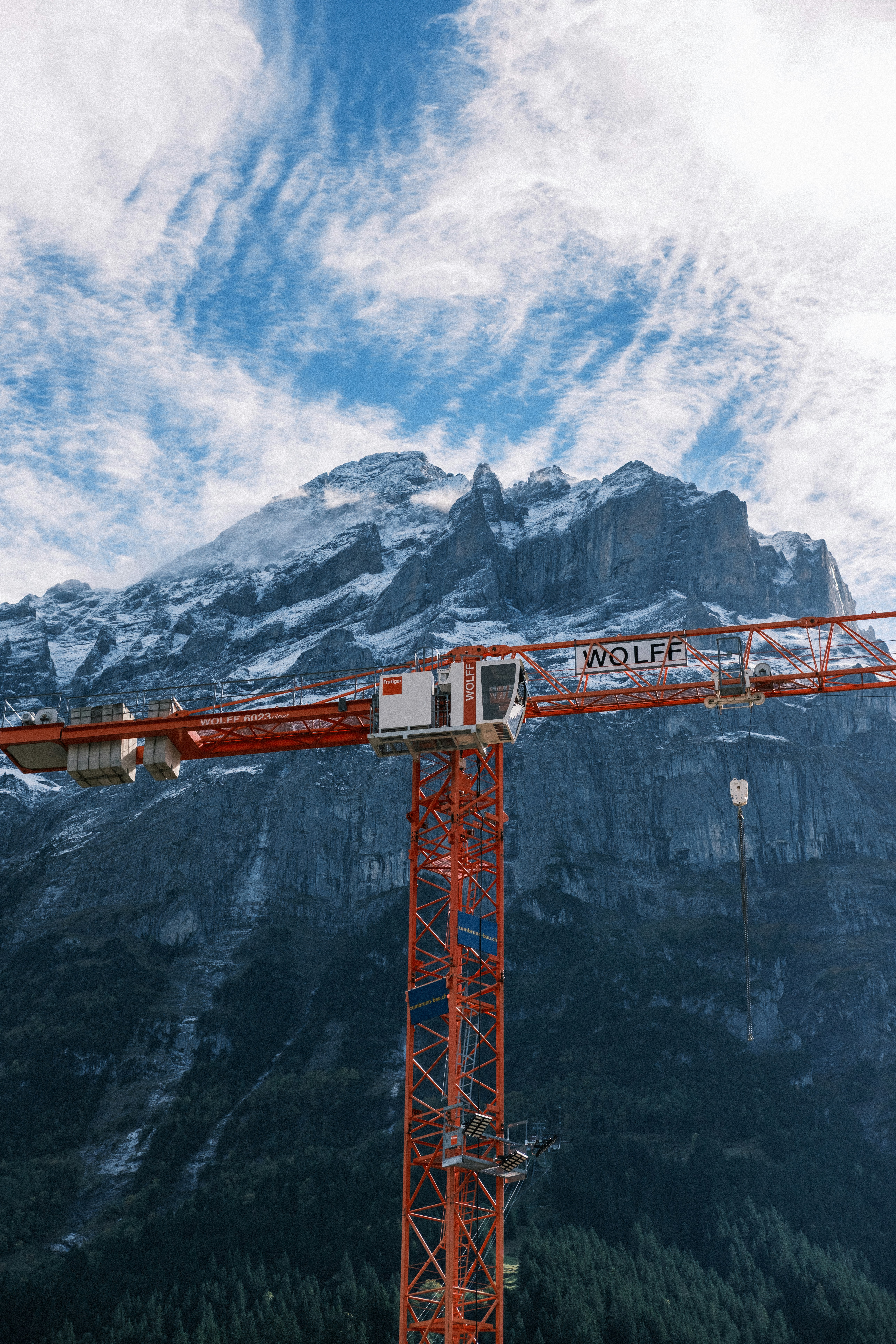 Crane Against Alpine Summit: Red Lattice Crowned by Snow