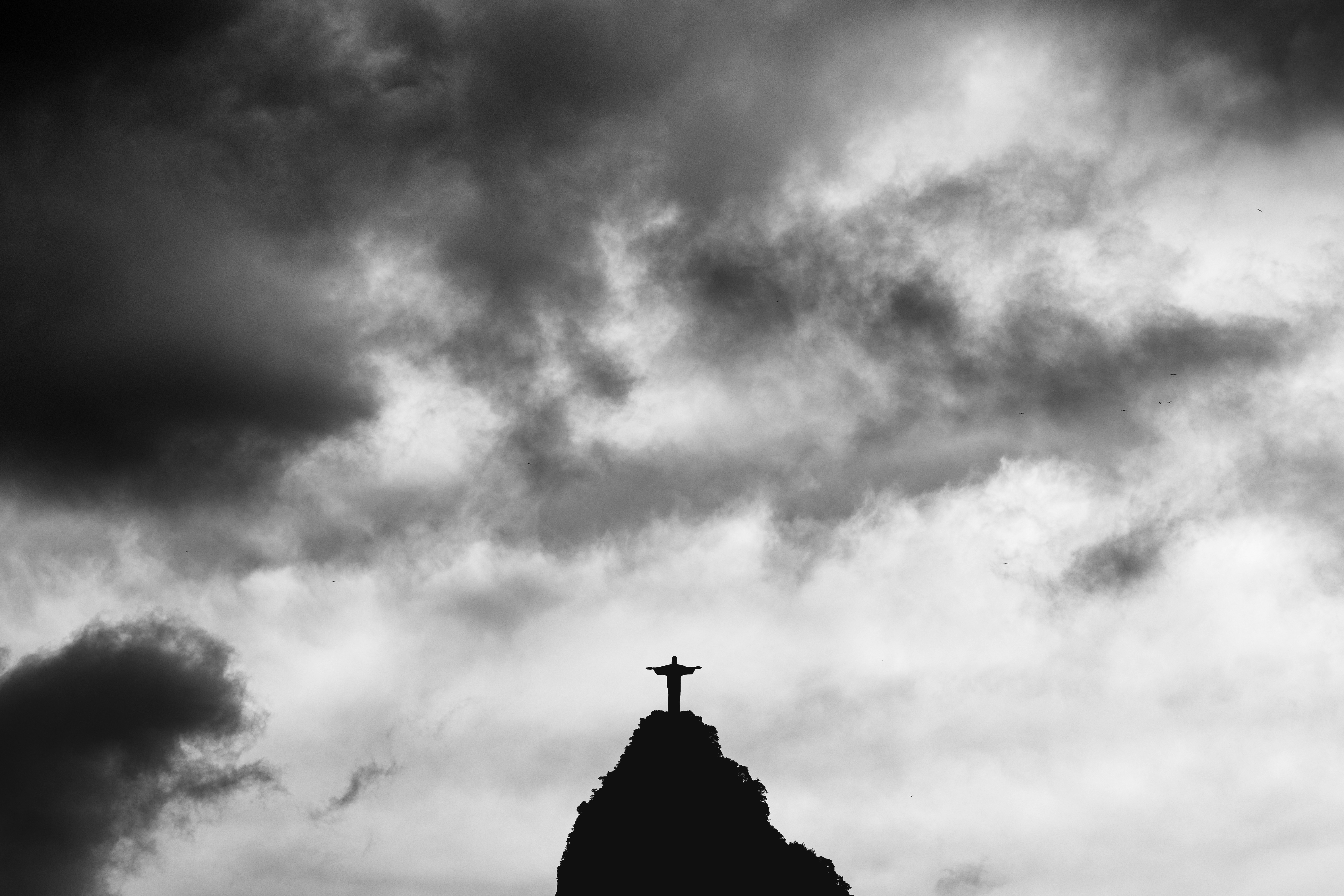 Silhouette on the Peak: A Lone Cross Against Stormy Skies
