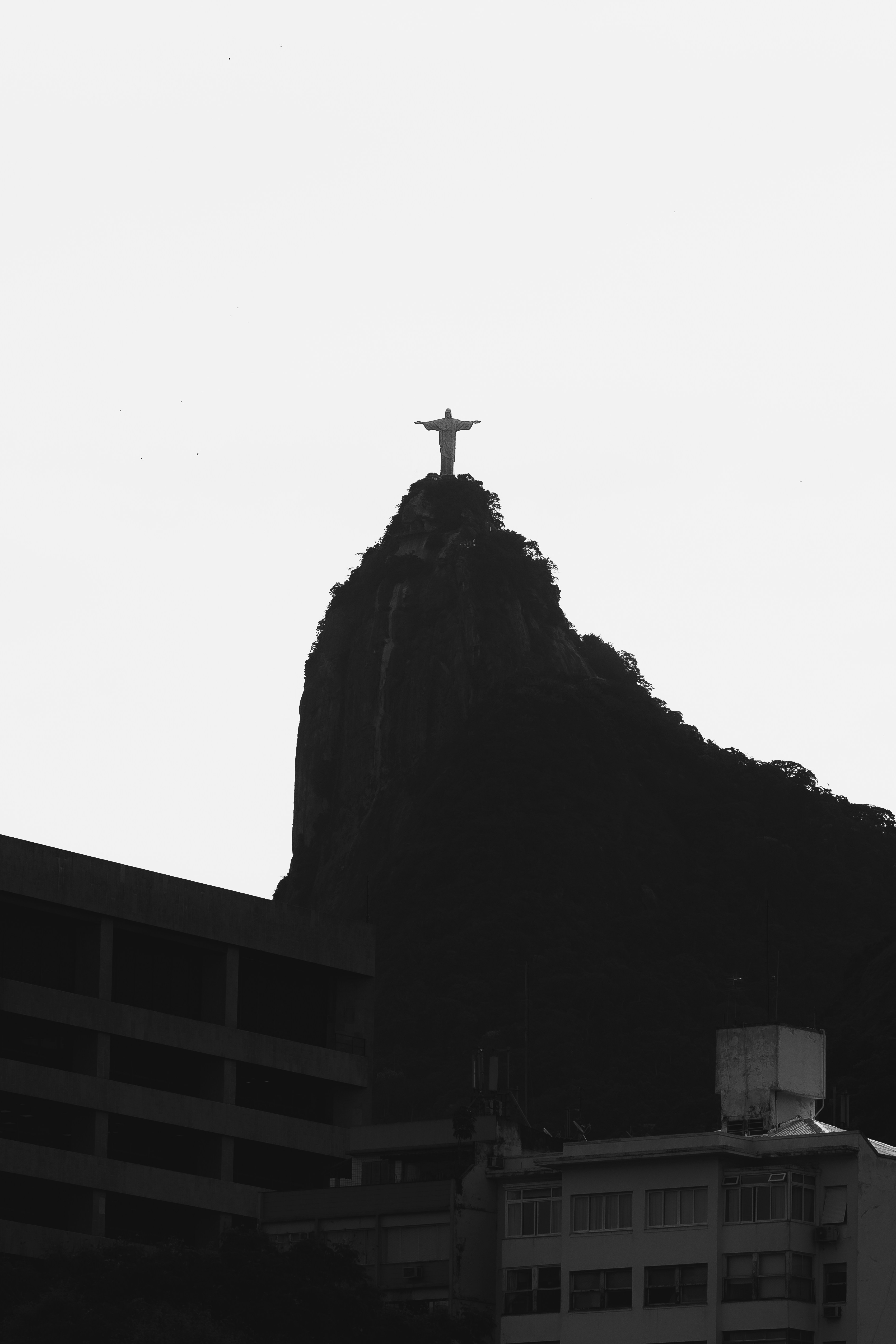 Cross atop a granite peak: silent silhouette above urban shadows