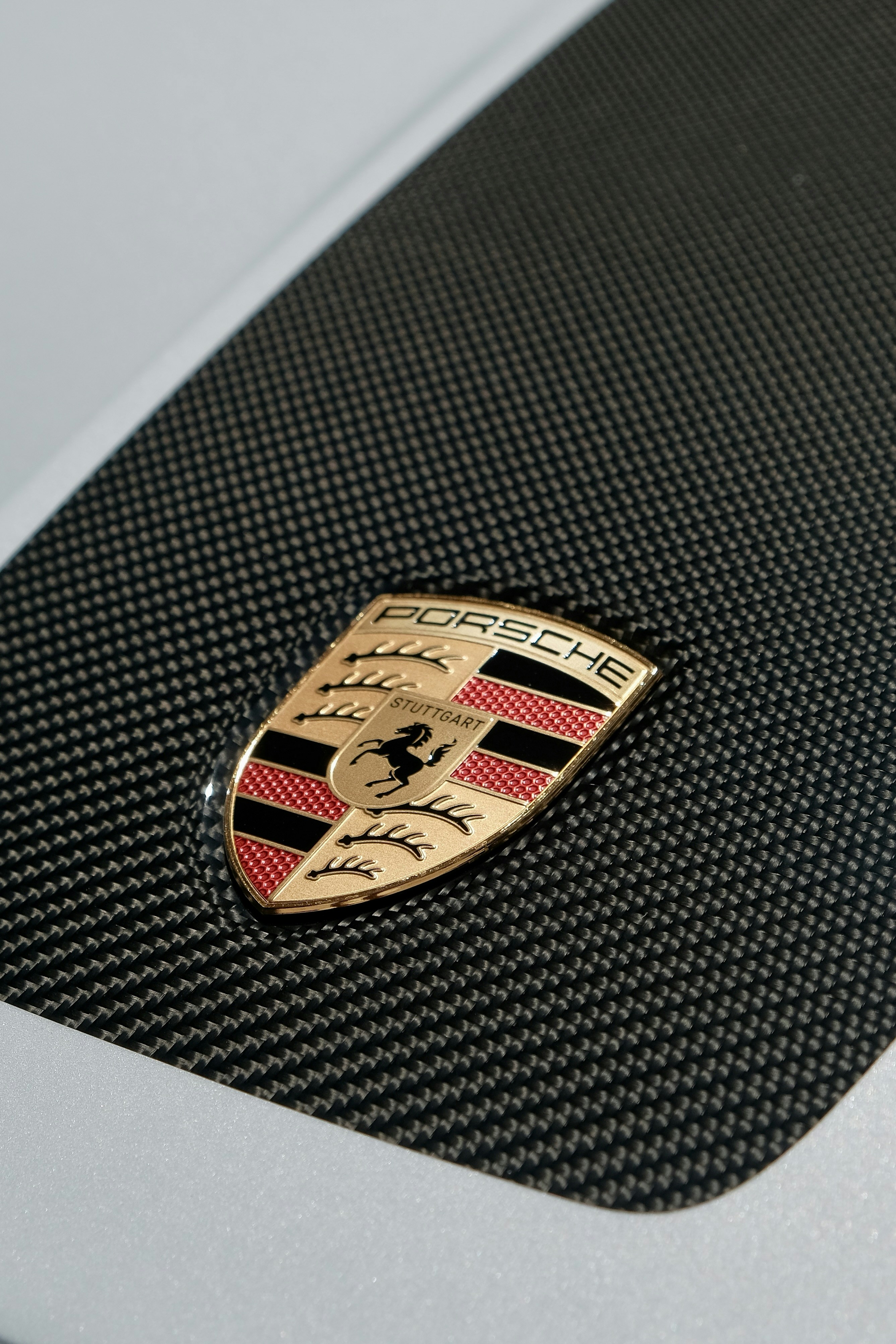 Emblem in Focus: Porsche Crest Resting on Carbon Weave