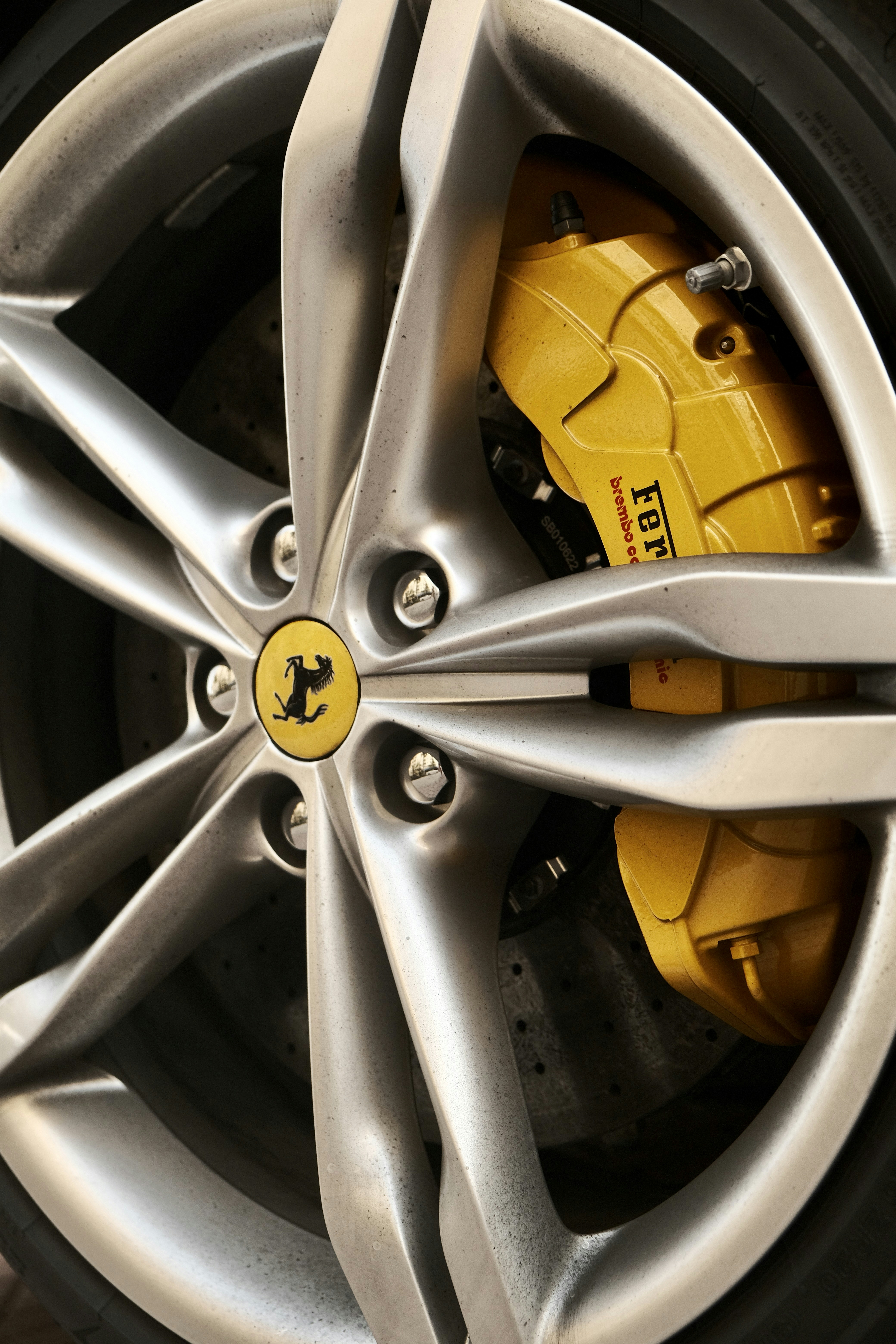 Ferrari Yellow: Close-Up of an Exposed Brake Caliper Behind Rim Spokes