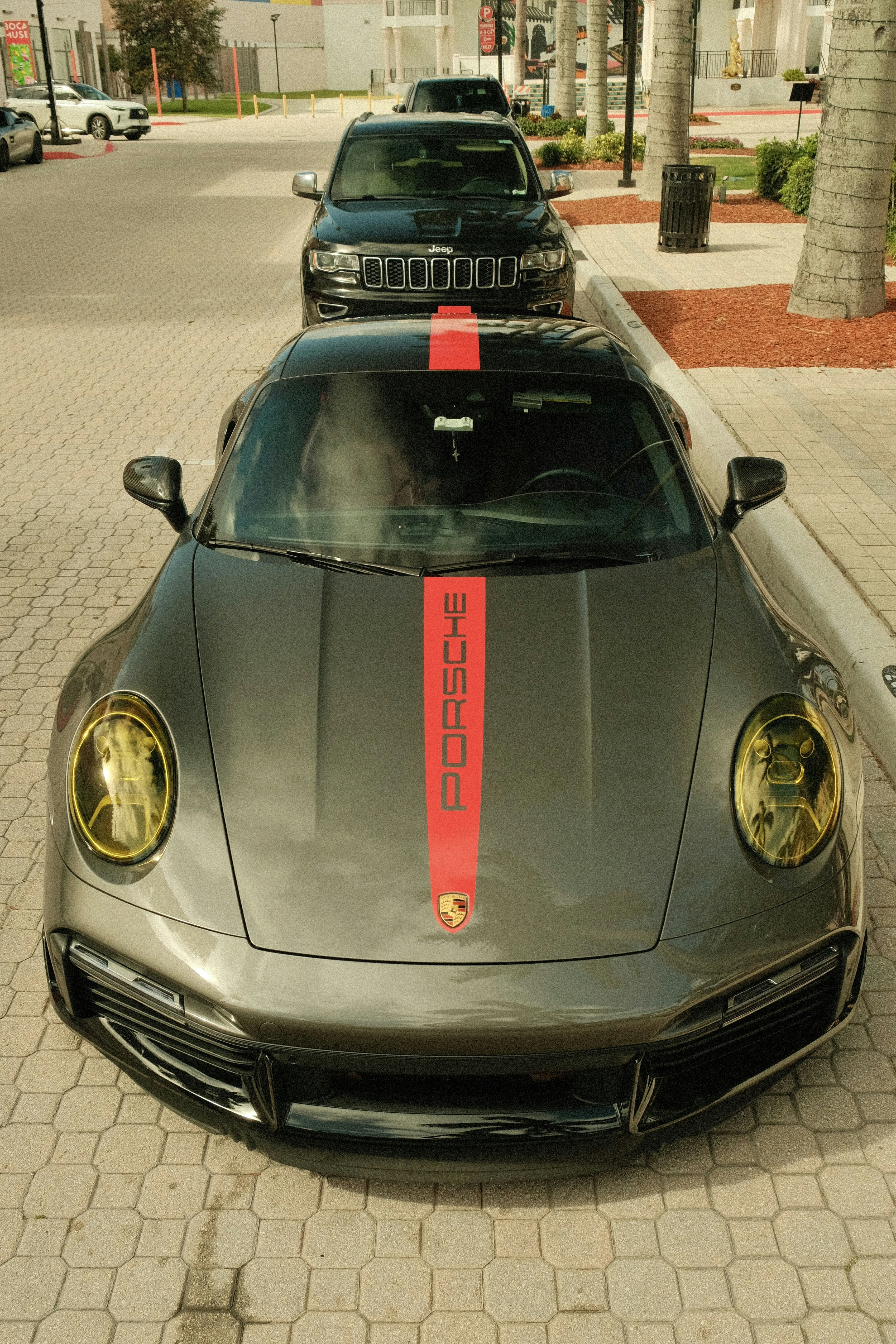 Front-and-Center Porsche: A Dark Gray coupe with a bold red racing stripe