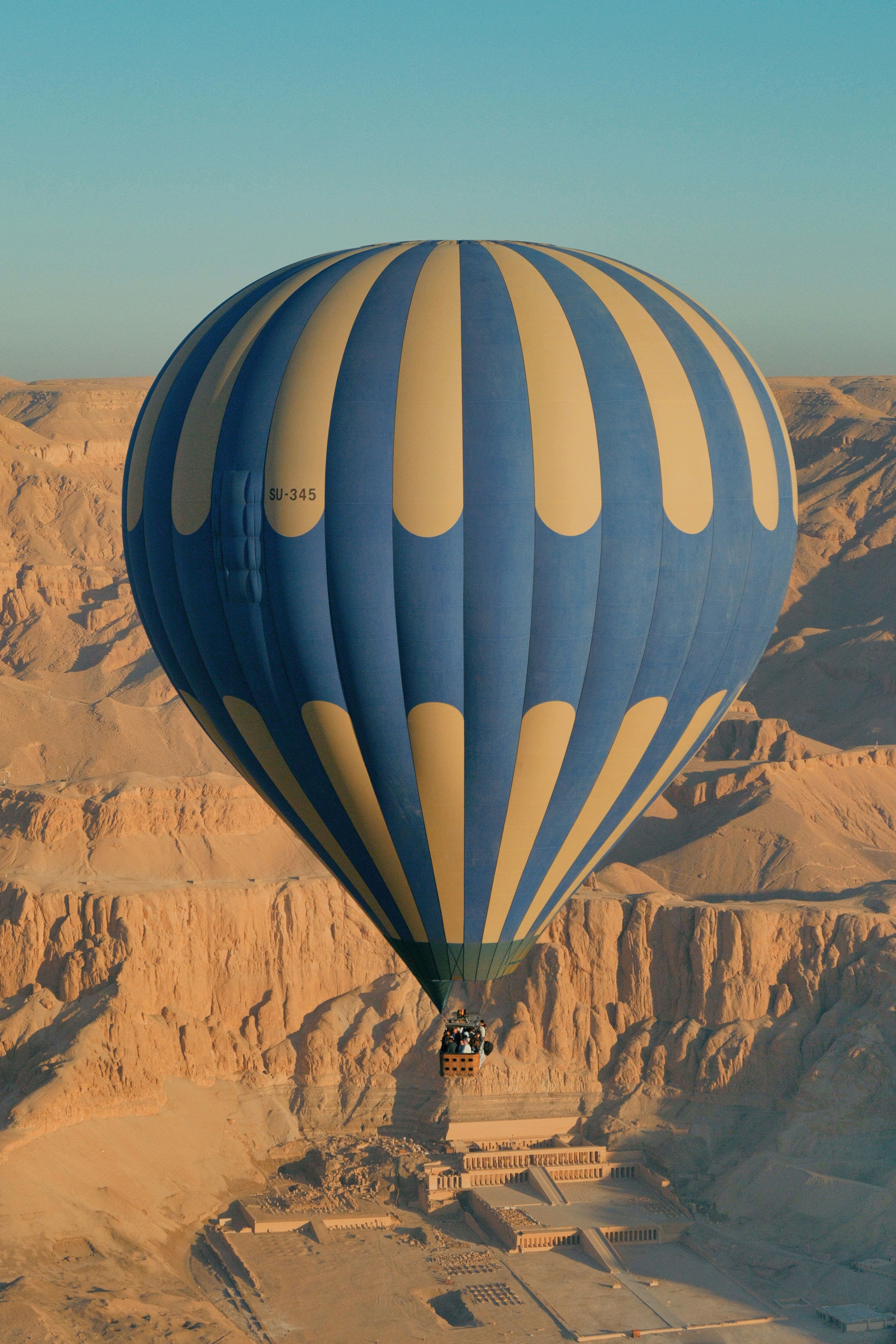 Desert Dawn Lift: Blue and Gold Balloon Above Ancient Cliffs
