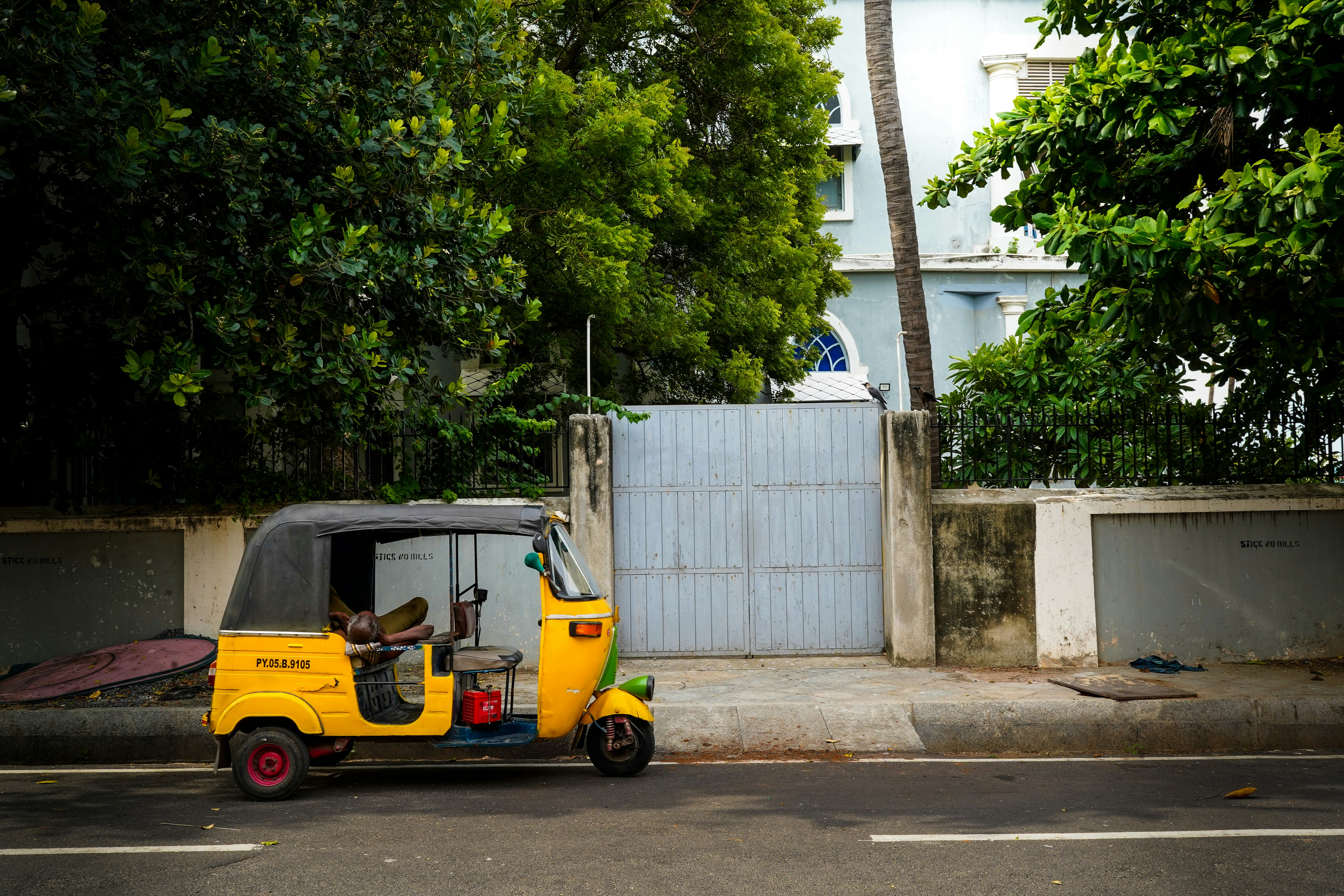 Yellow Auto Rickshaw at the Gate: A Quiet Street Scene