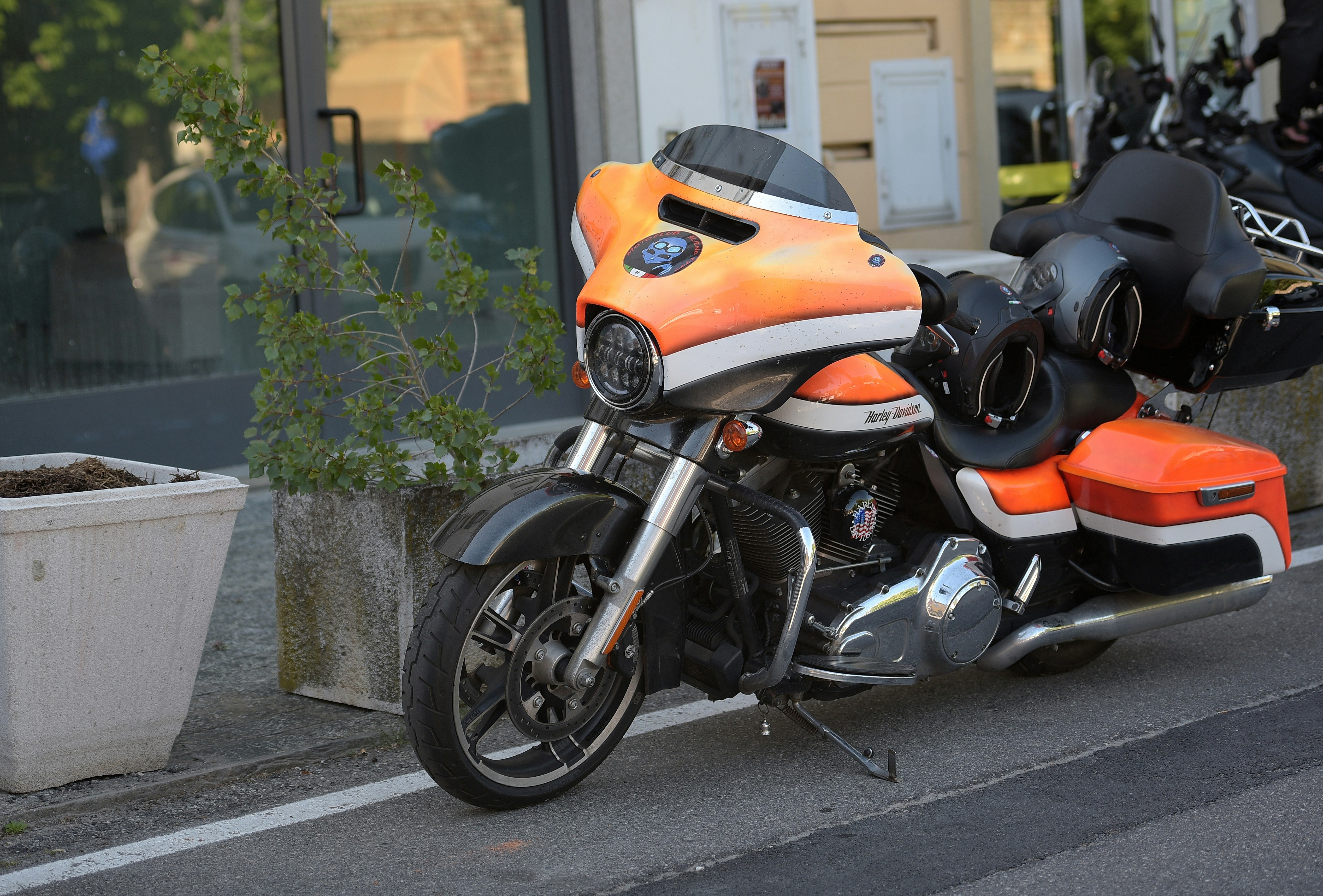 Orange touring motorcycle anchored on city street with chrome gleam and saddlebags