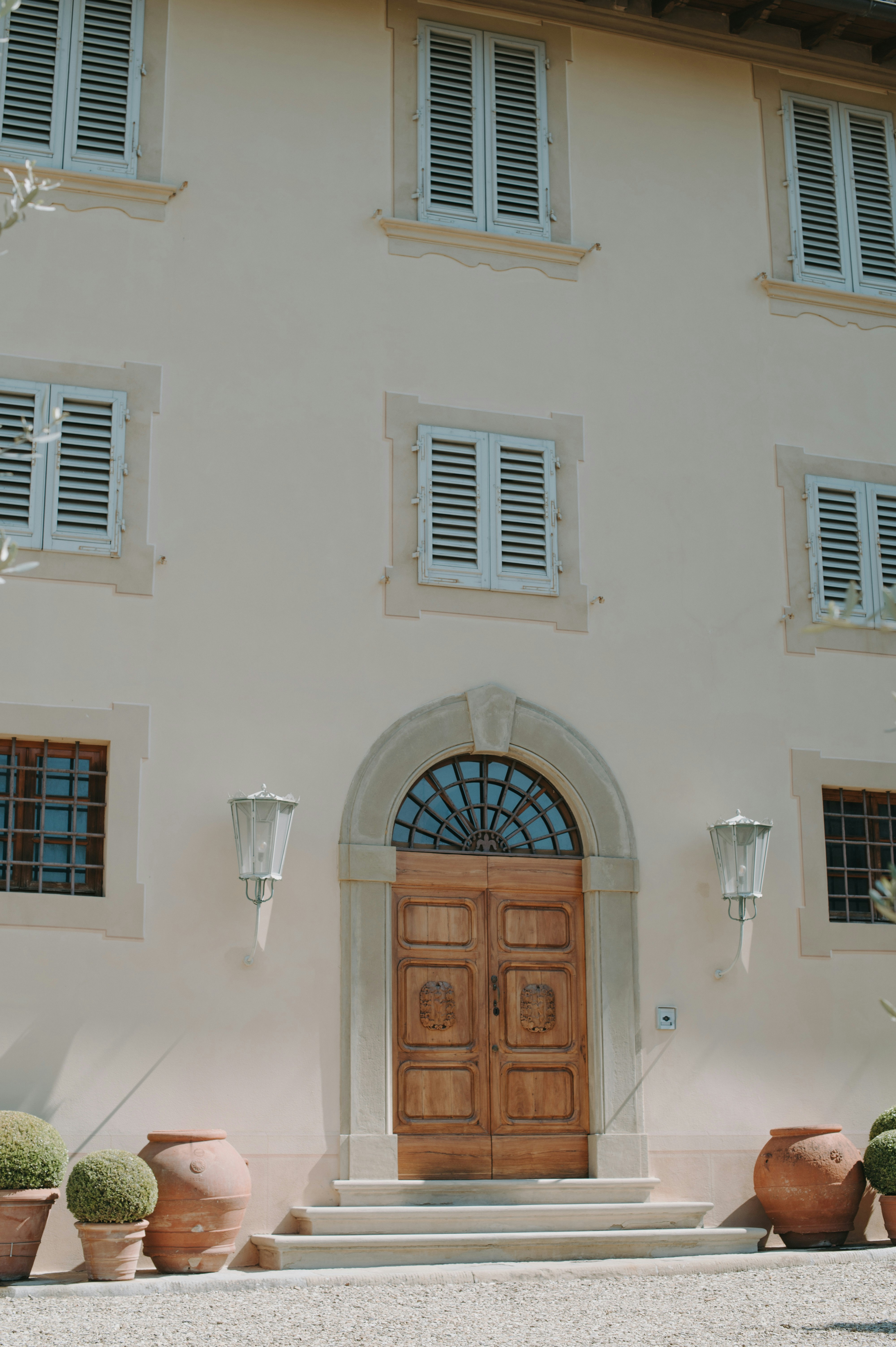 Arched Doorway Symphony: A Tuscan-cream Facade with Sculpted Entry