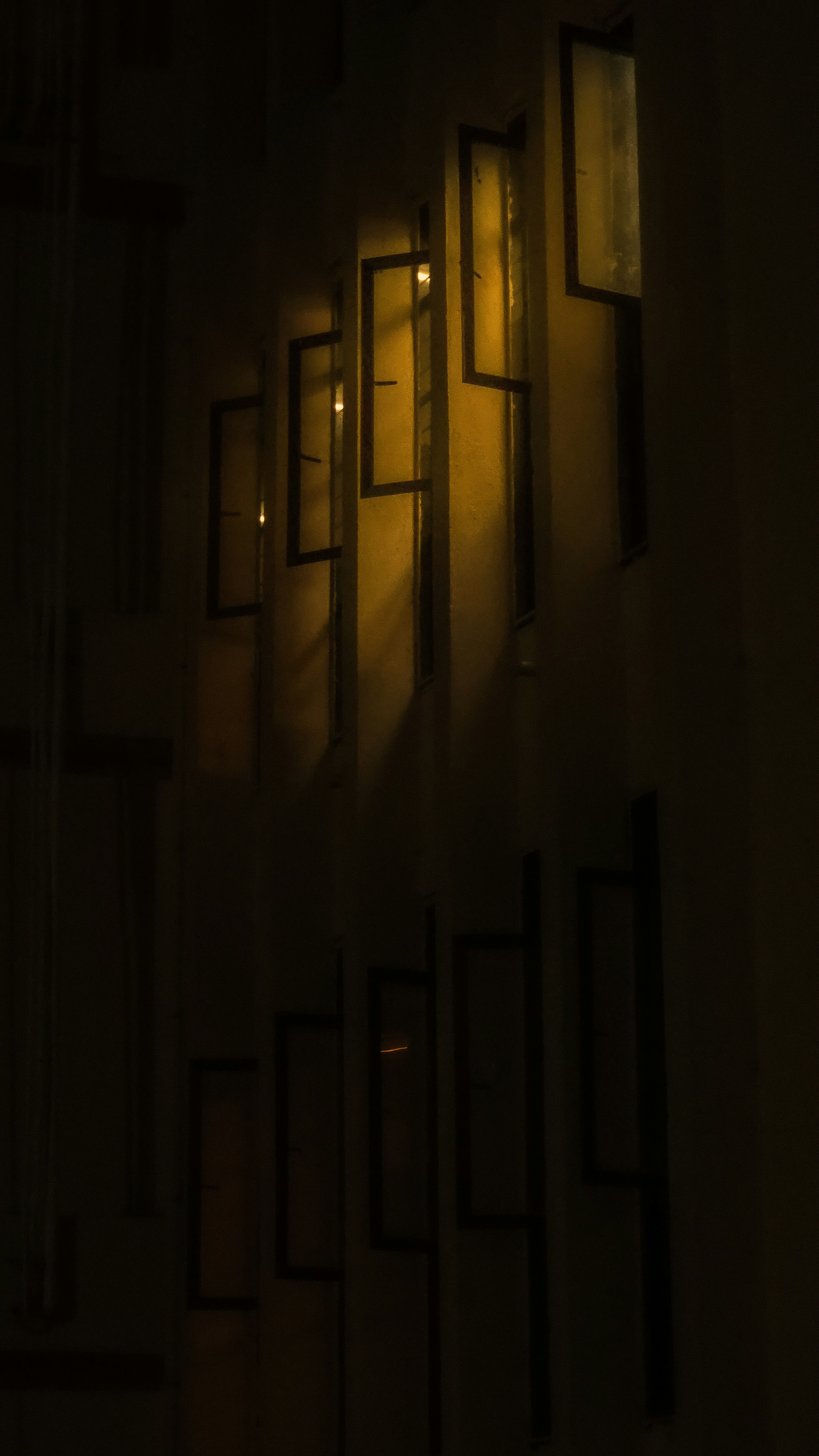 Golden Frames in the Night: Echoes of Light on a Wall of Windows