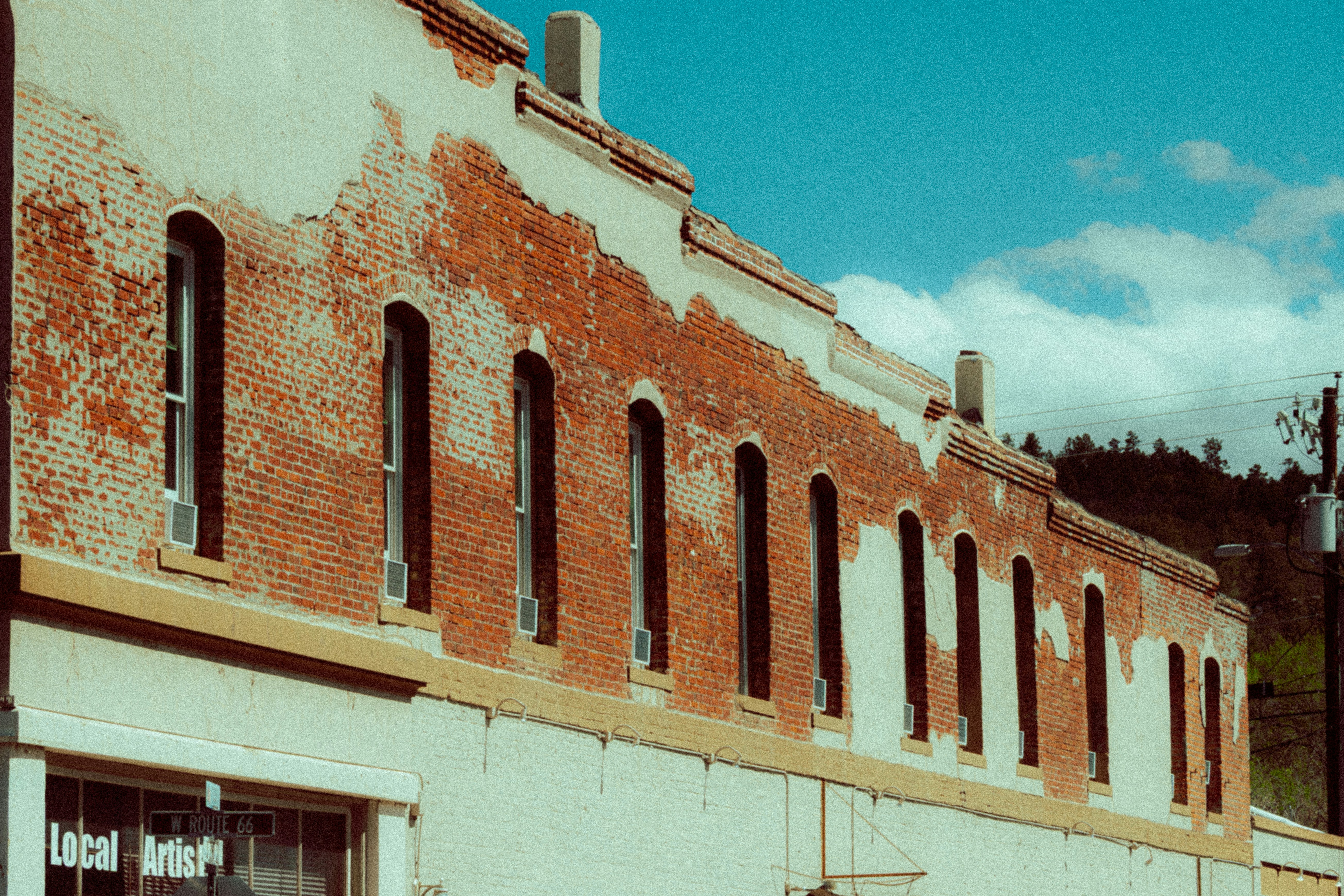 Brickwork Echoes: A Weathered Row of Arched Windows on a Sunny Main Street