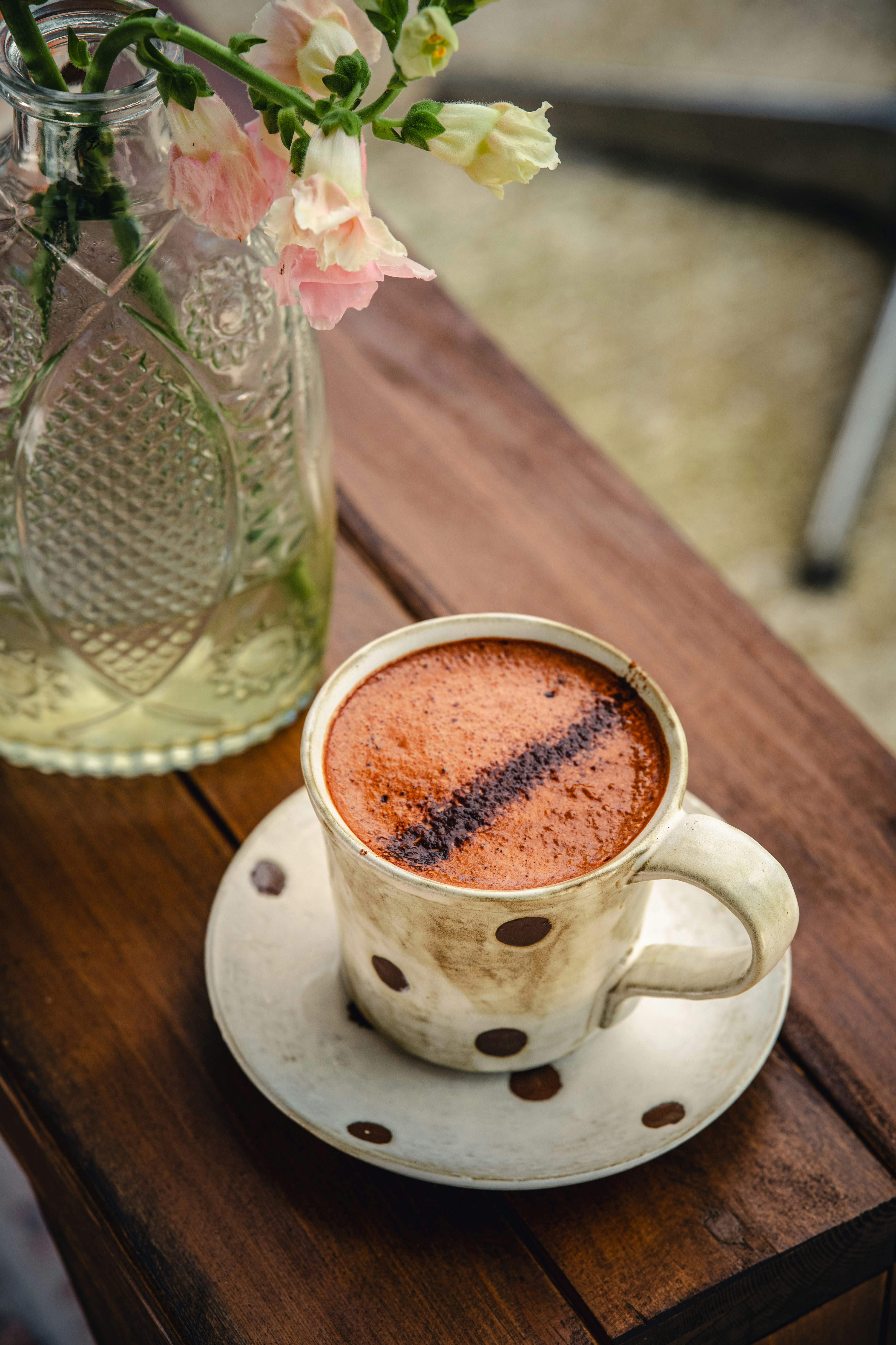 Cup of Cocoa on a Rustic Table with a Delicate Vase of Flowers