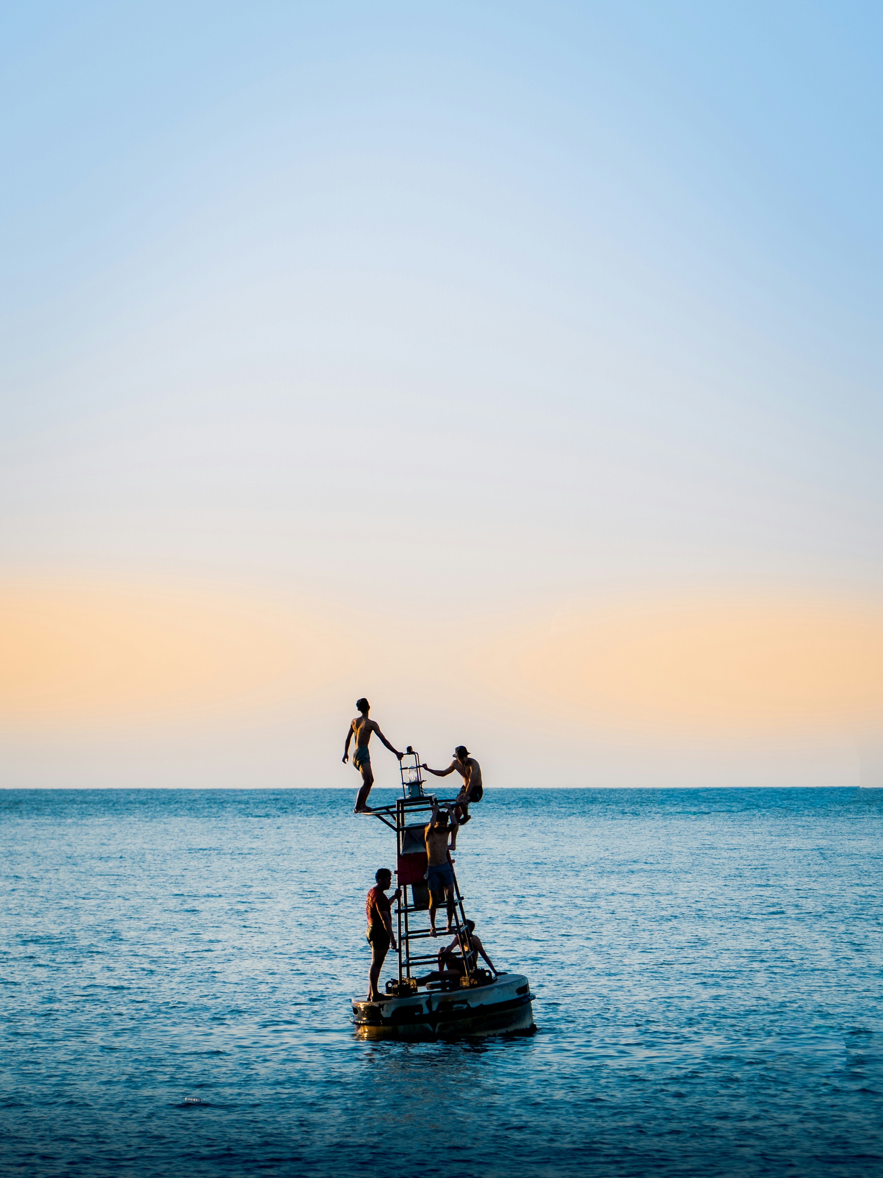 Lifeline at Dusk: Climbers on a Tiny Platform Above Sea