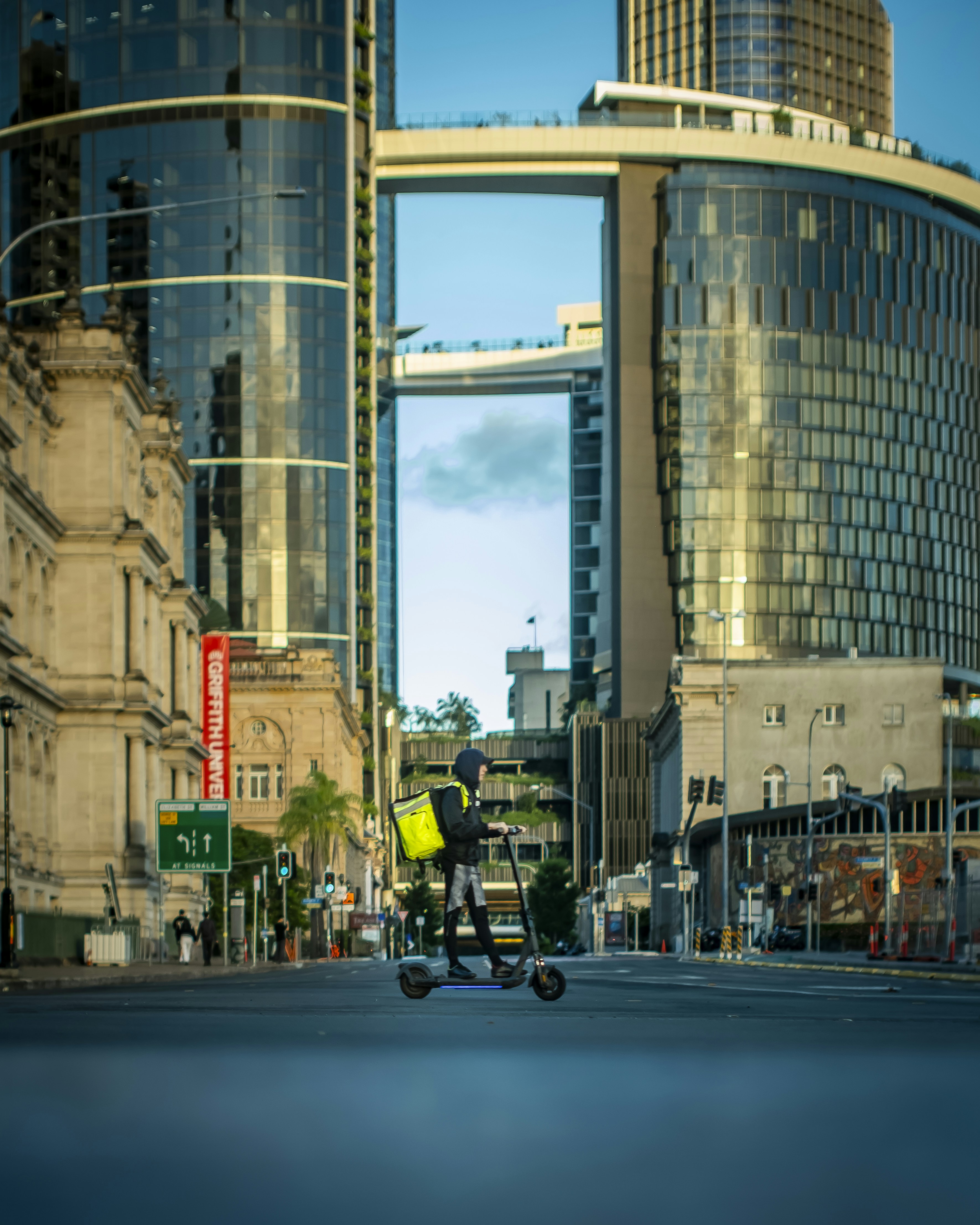 Urban Glide: Scooterist under the Arch of Glass Skyscrapers