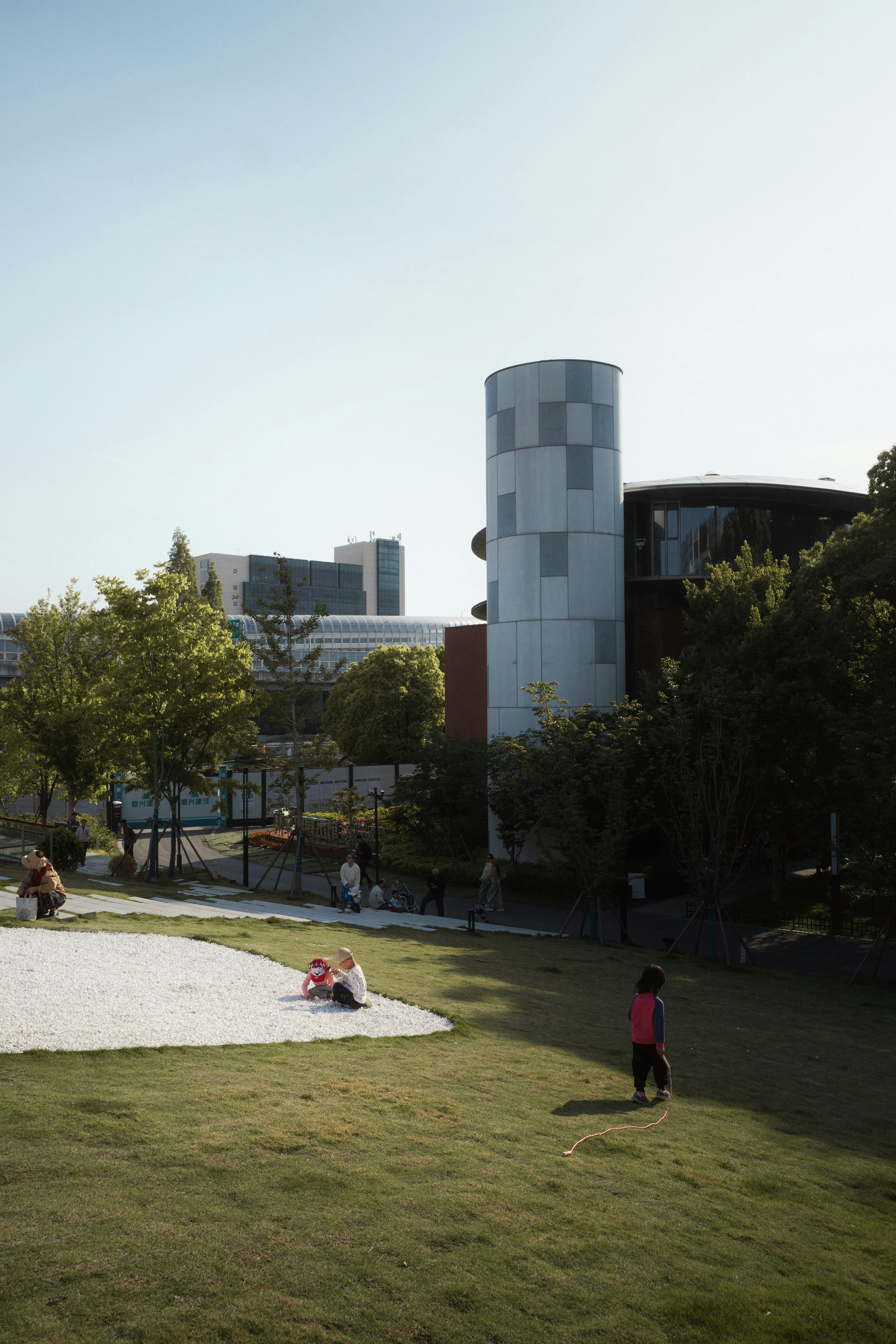 Sunlit Campus Playground Under Modern Cylindrical Tower
