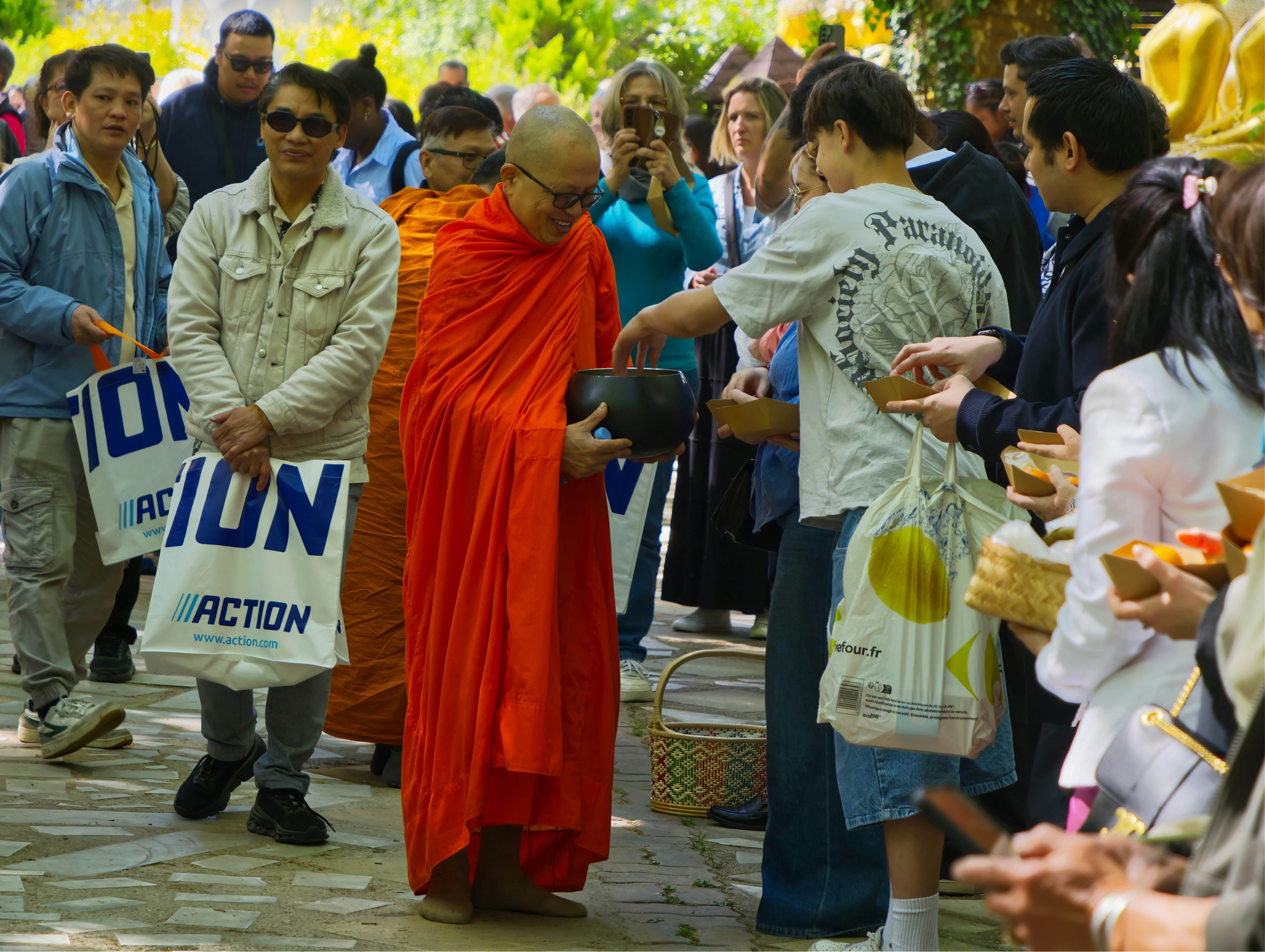 Monk and devotees share offerings at a sunlit courtyard gathering