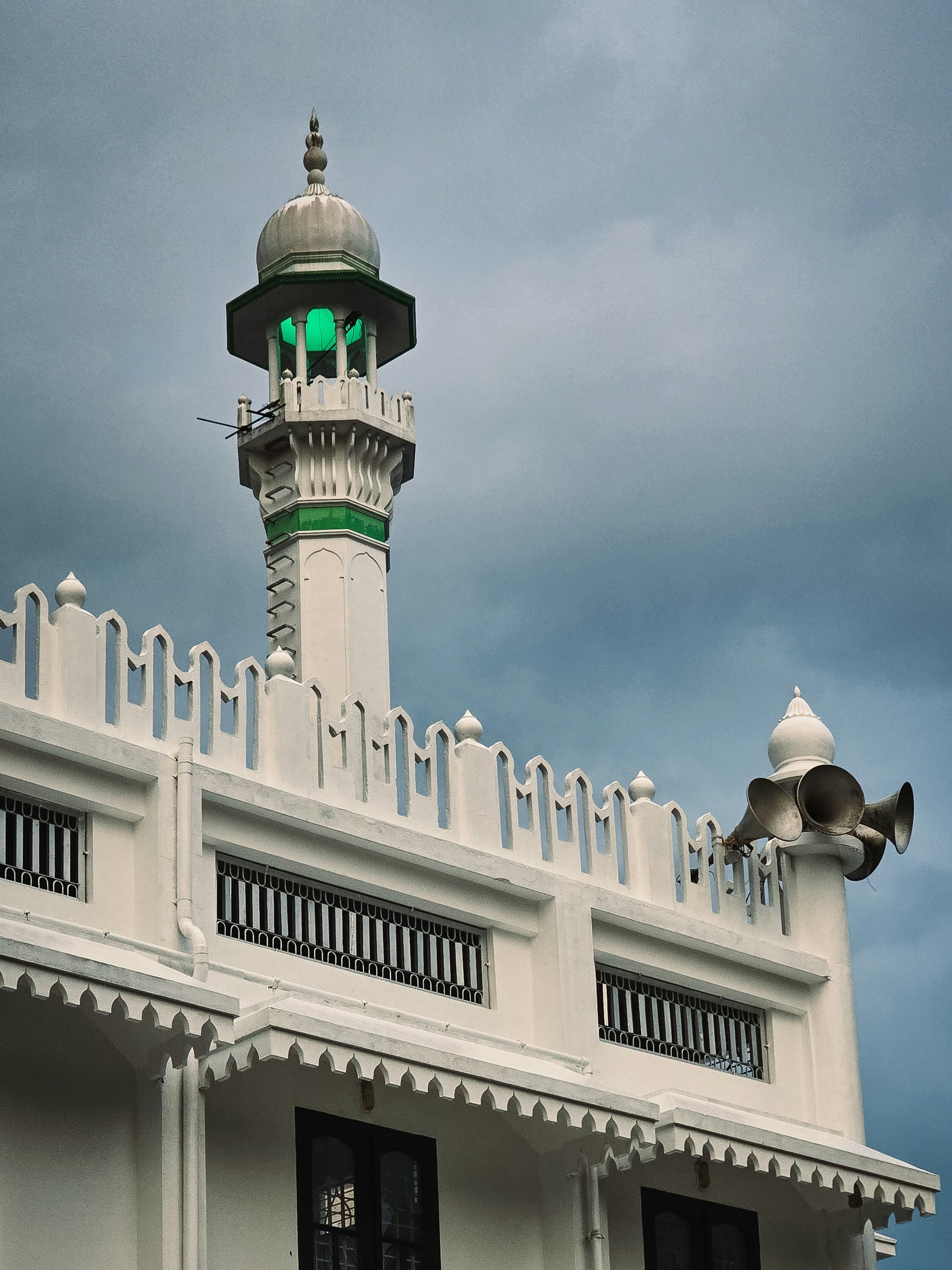 Green-topped minaret rises above a white intricate facade