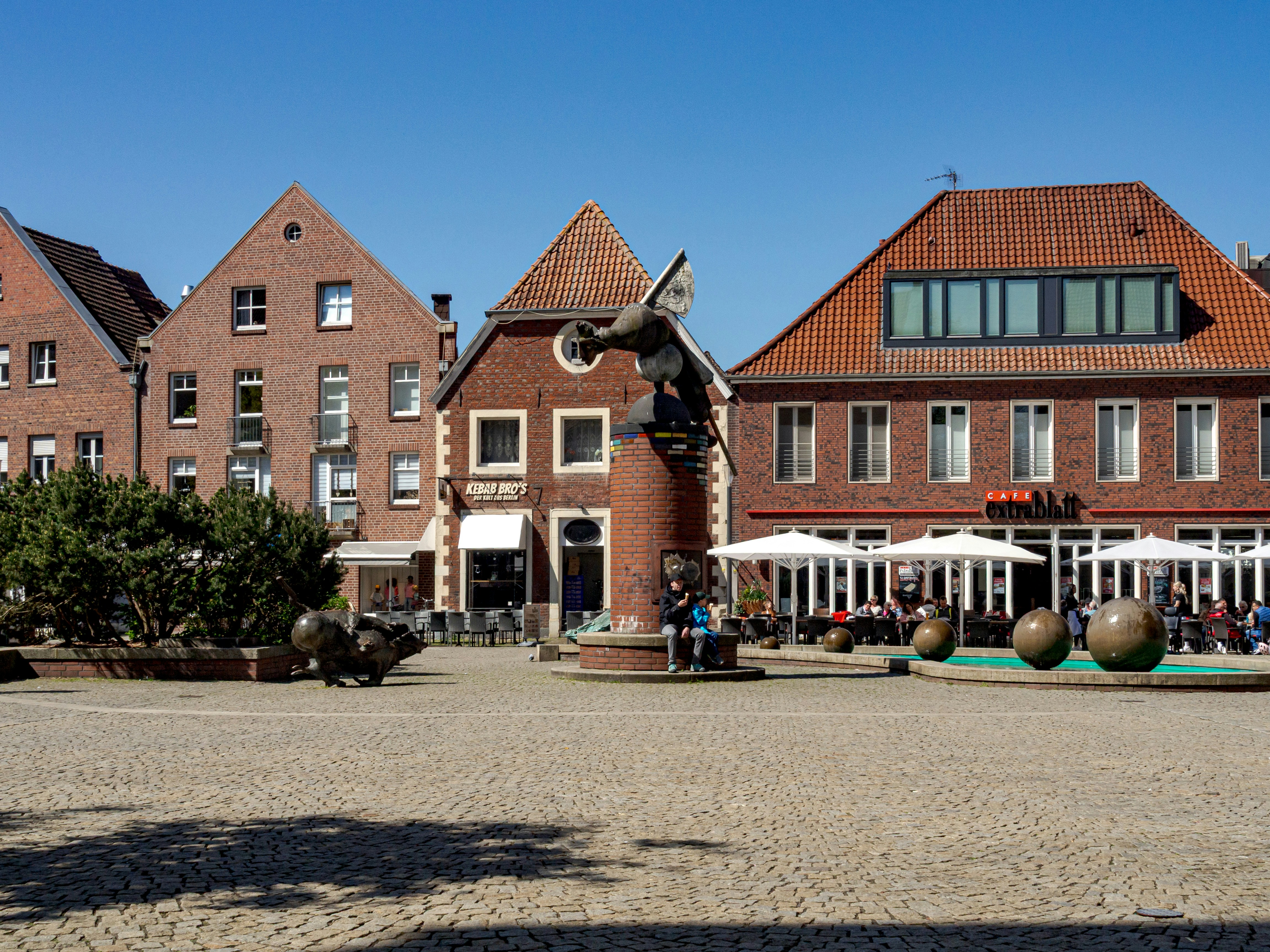 Sculpted Seated Winged Figure Guarding a Brick Town Square