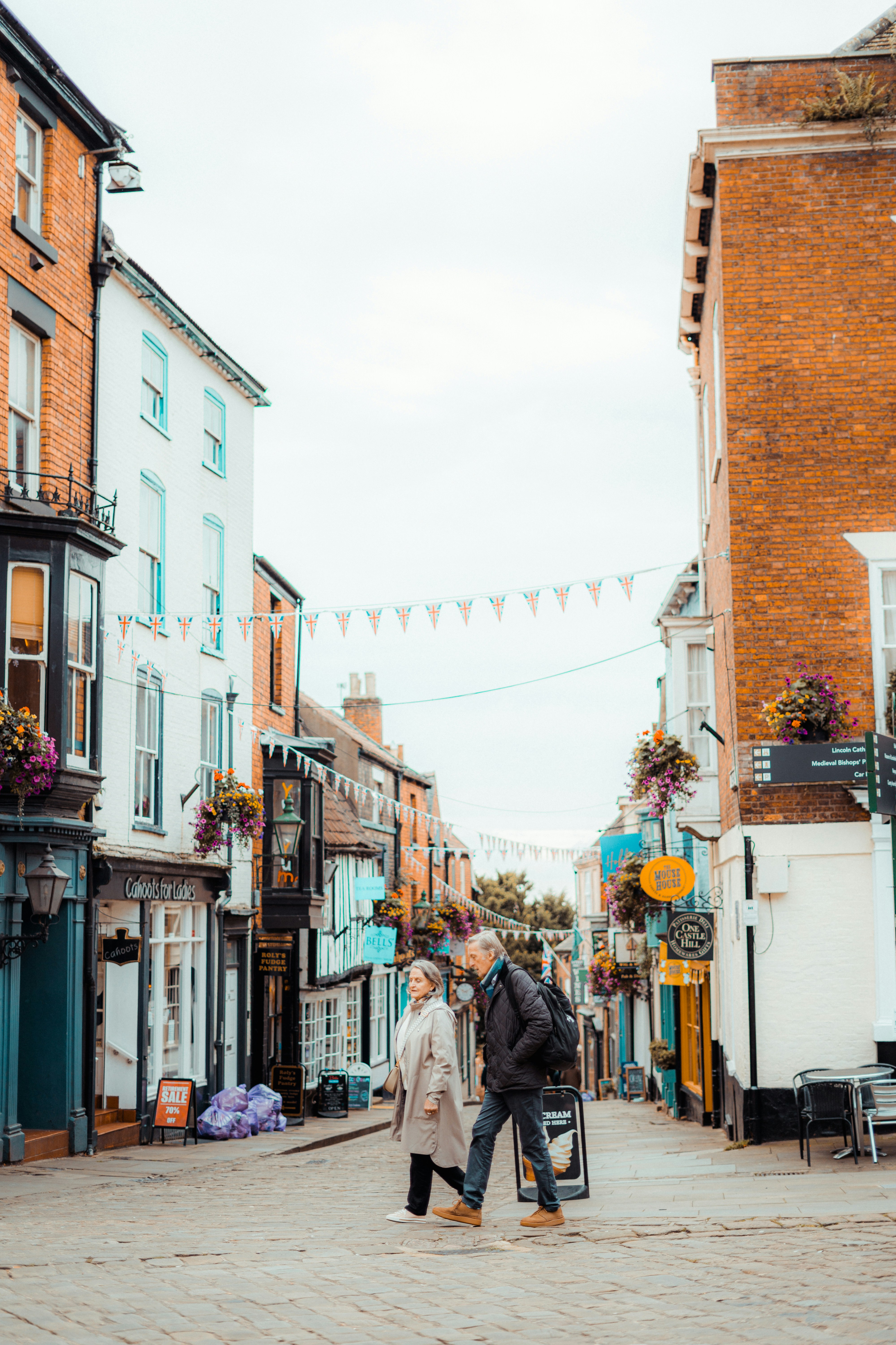 Quiet couple strolls through a sunlit, bunting-draped street