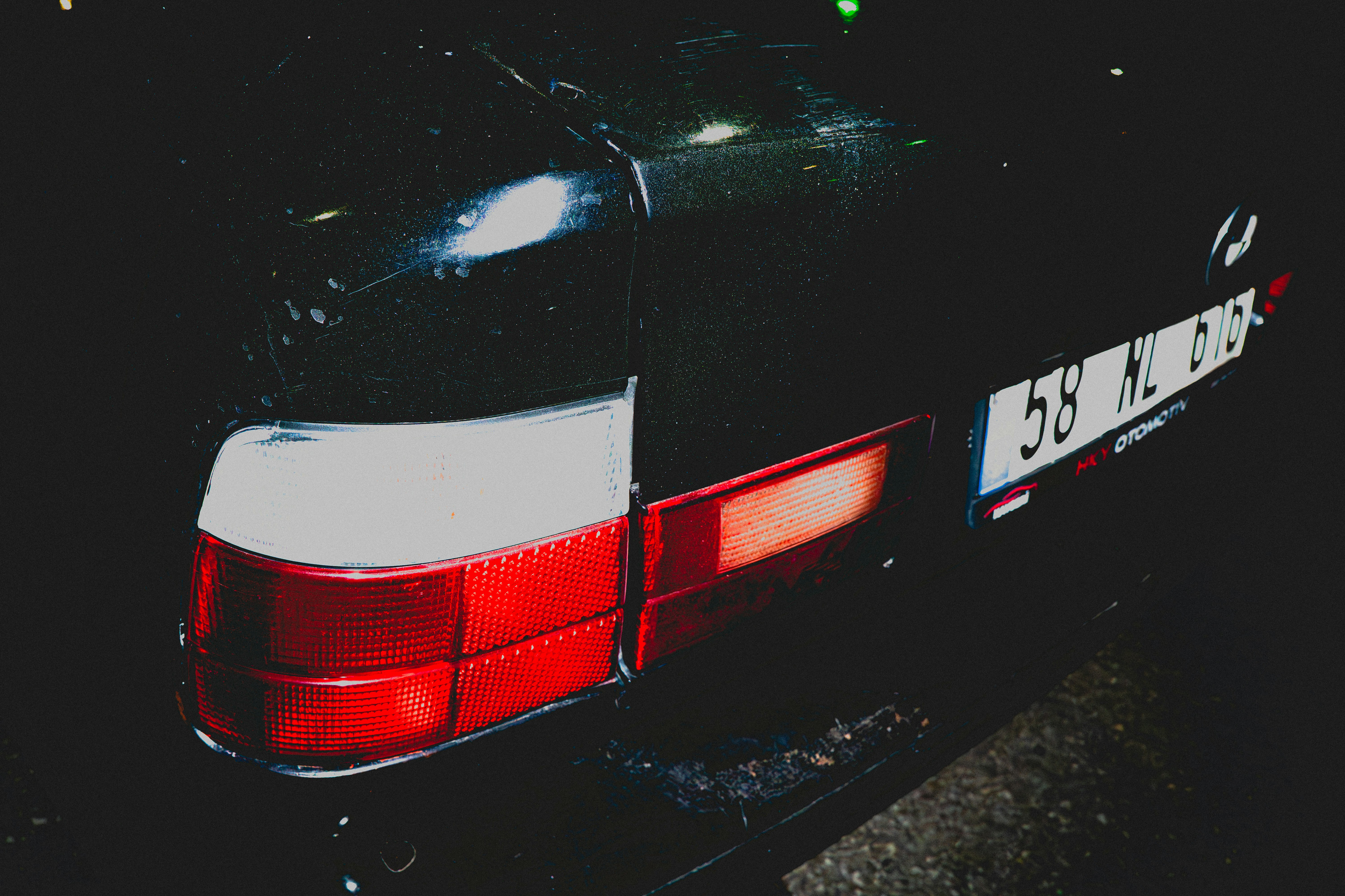 Night-shaded Car Rear: Faded Plate and Red Tail Lights