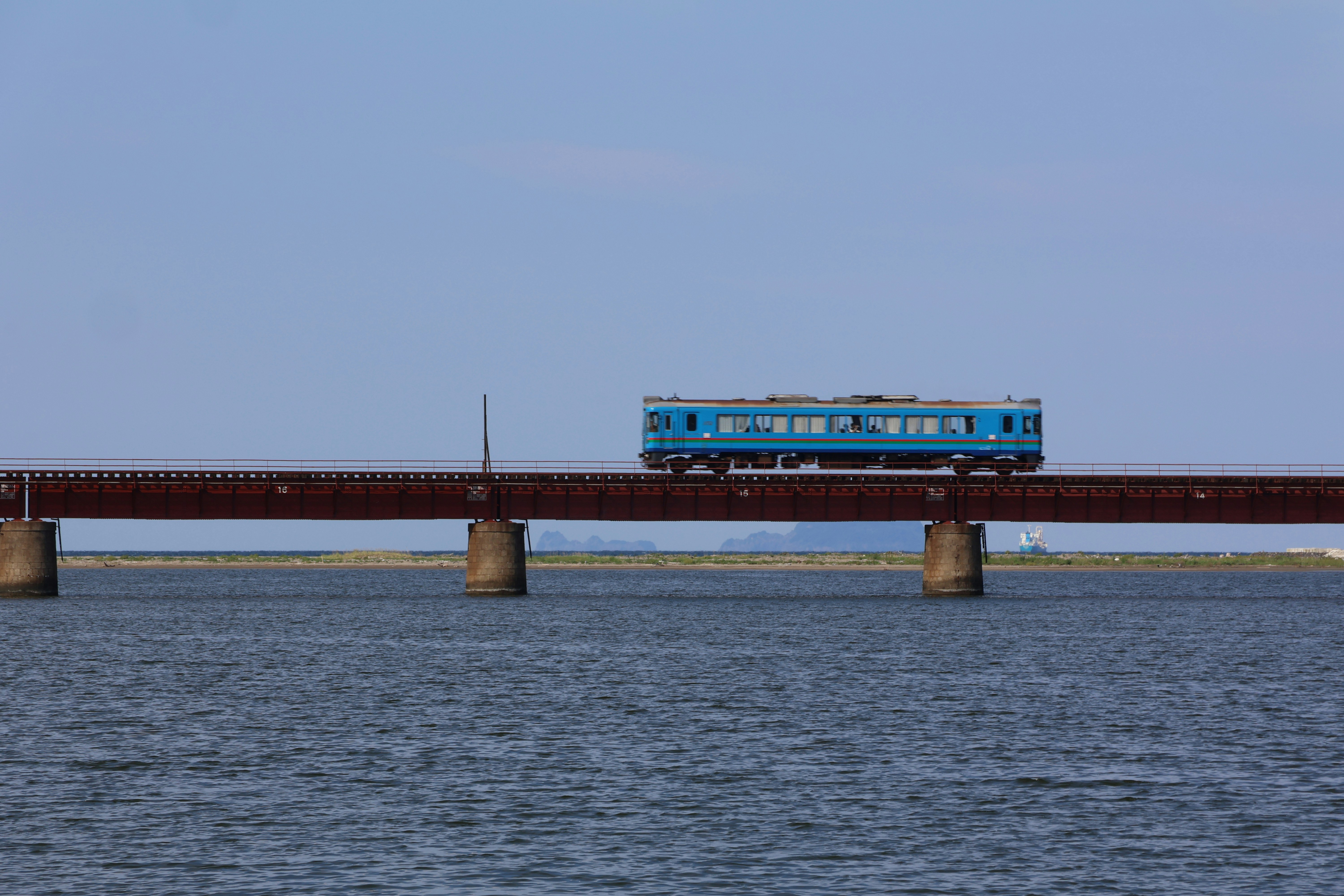 Blue Railcar Crossing a Distant Waterway