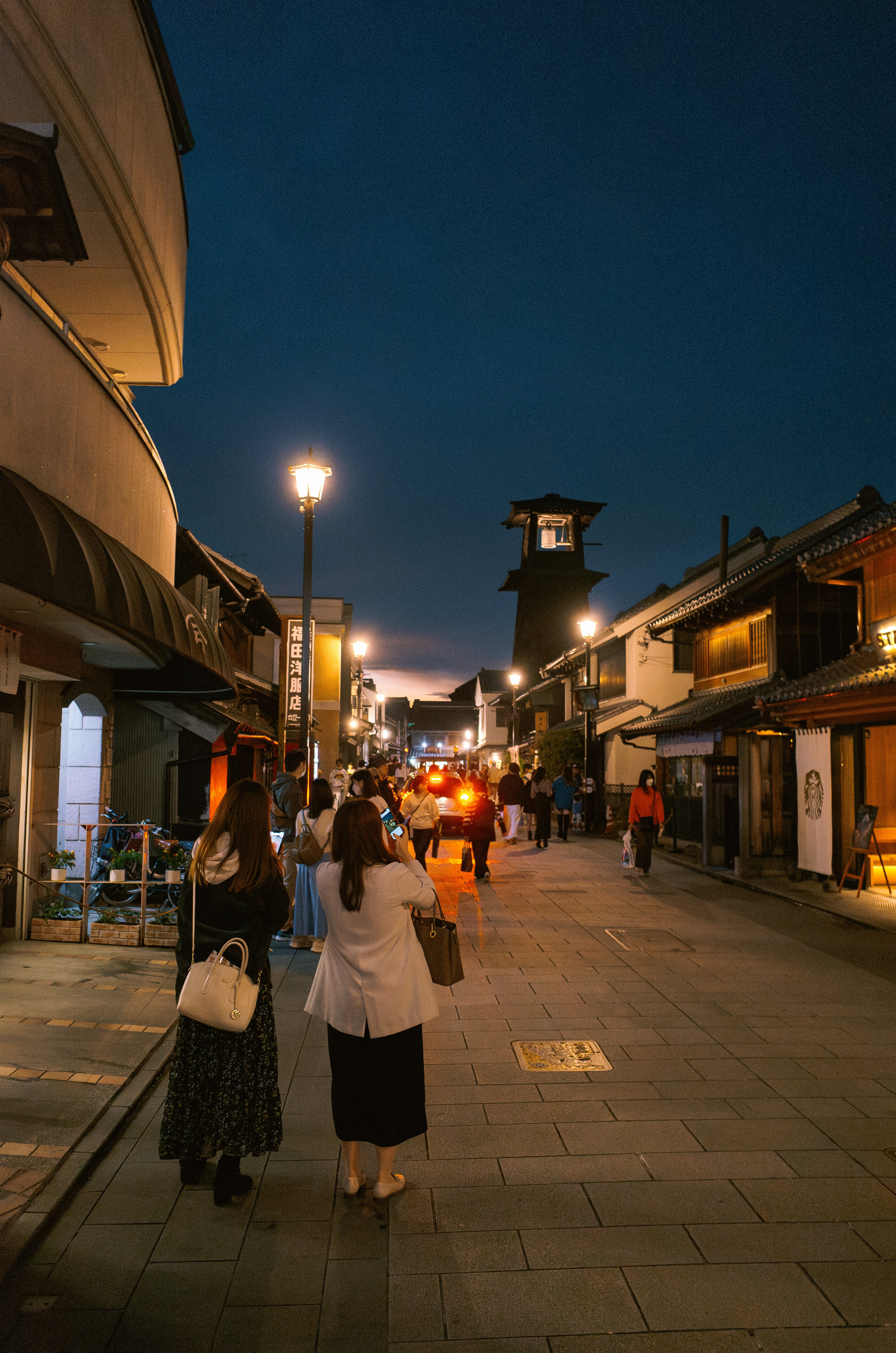 Evening Street in a Traditional Town with People and Warm Lantern Light