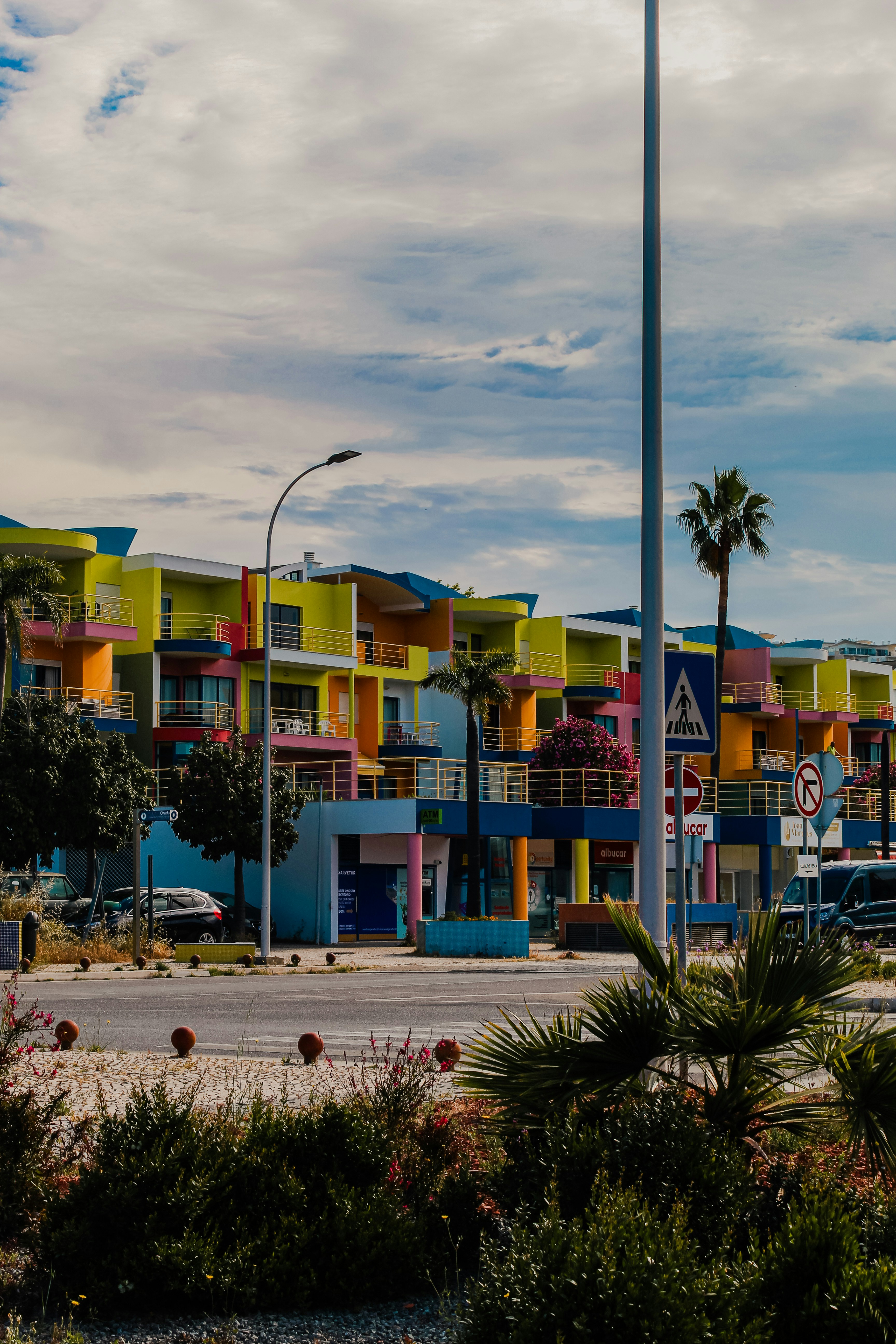 Colorful modern buildings with balconies and palm trees.