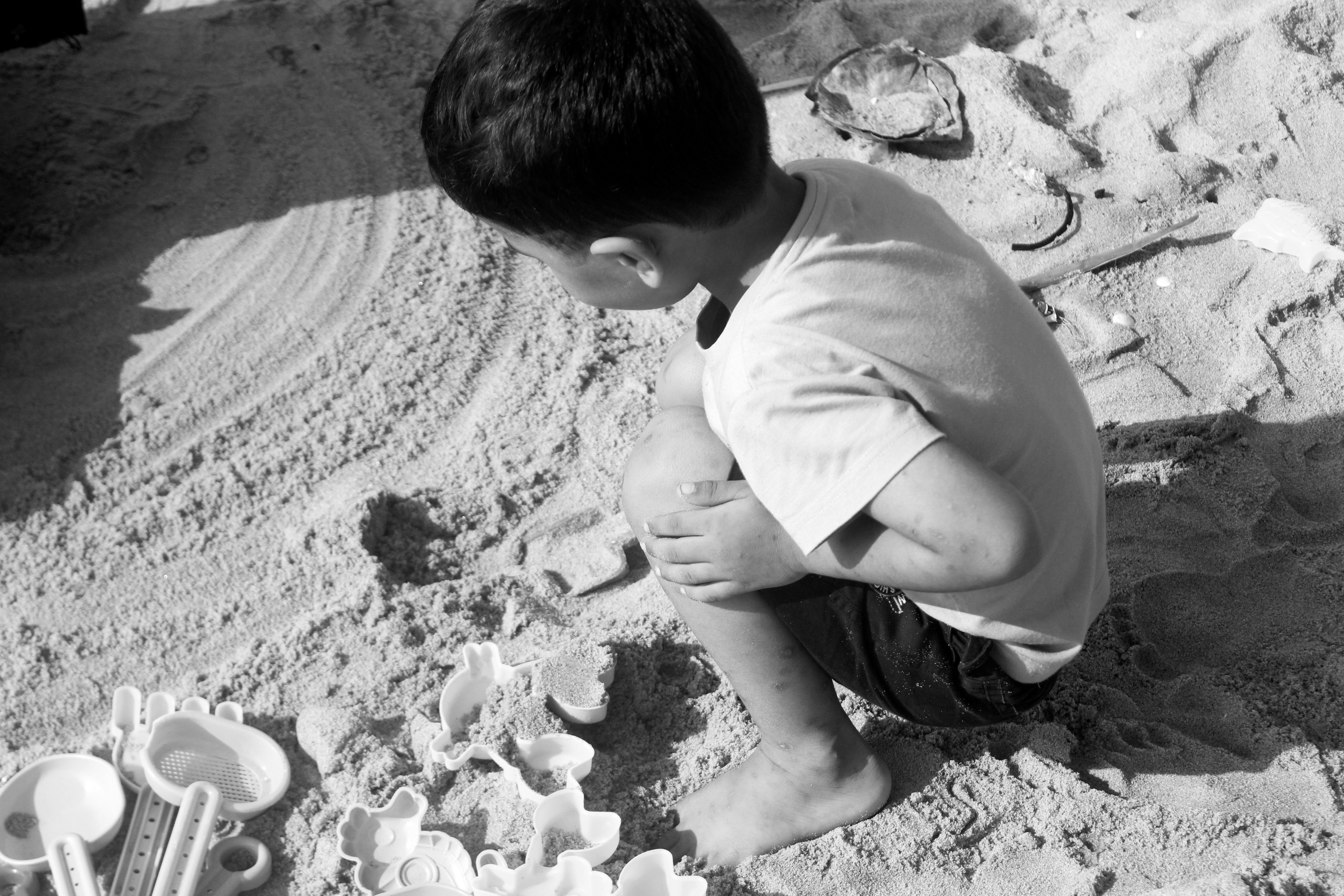 Tiny Architect of Sand: A Curious Boy Amid Toy Mounds