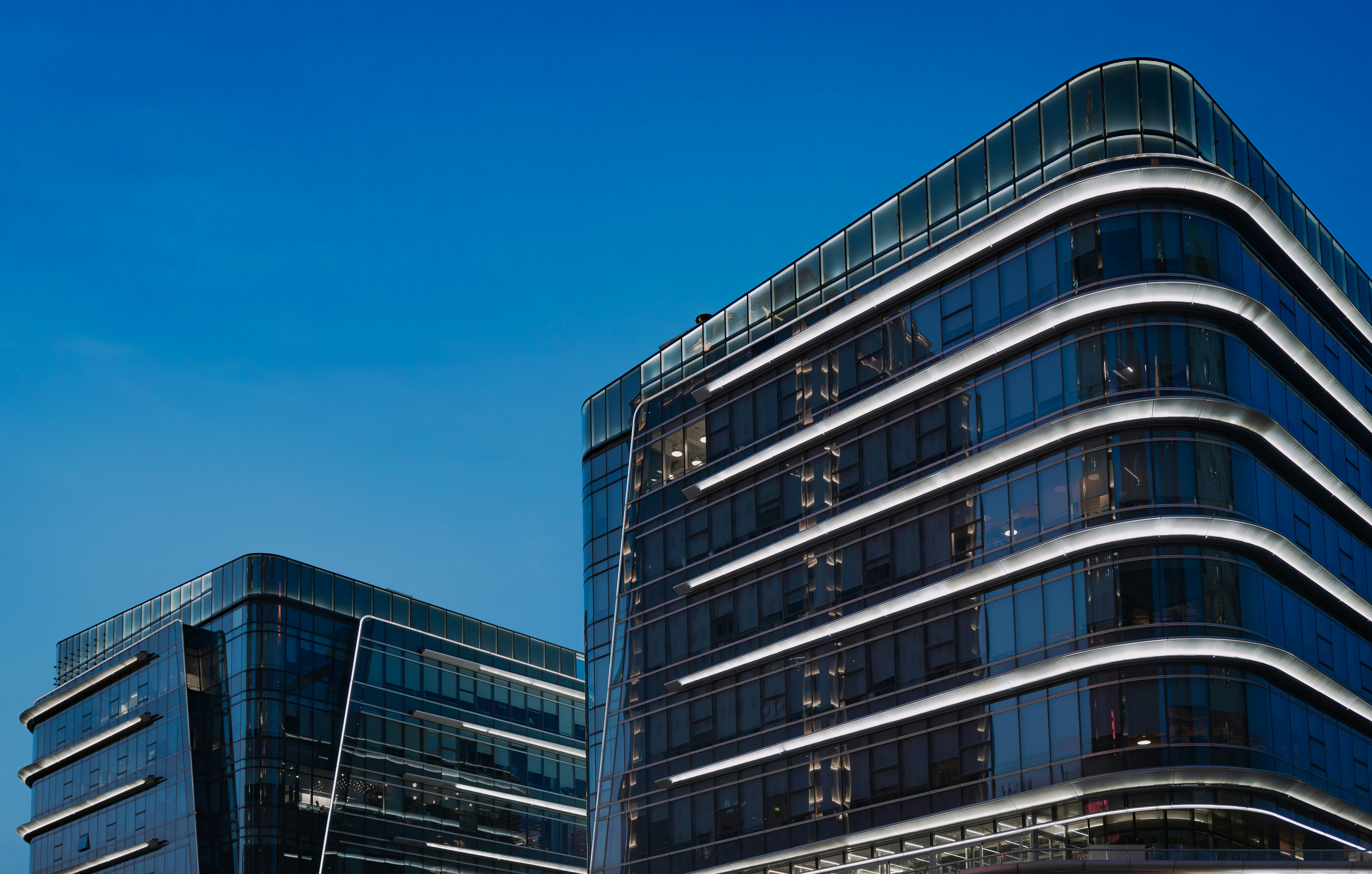 Curved Glass Ascendancy: A Duo of Modern Facades Reaching the Sky