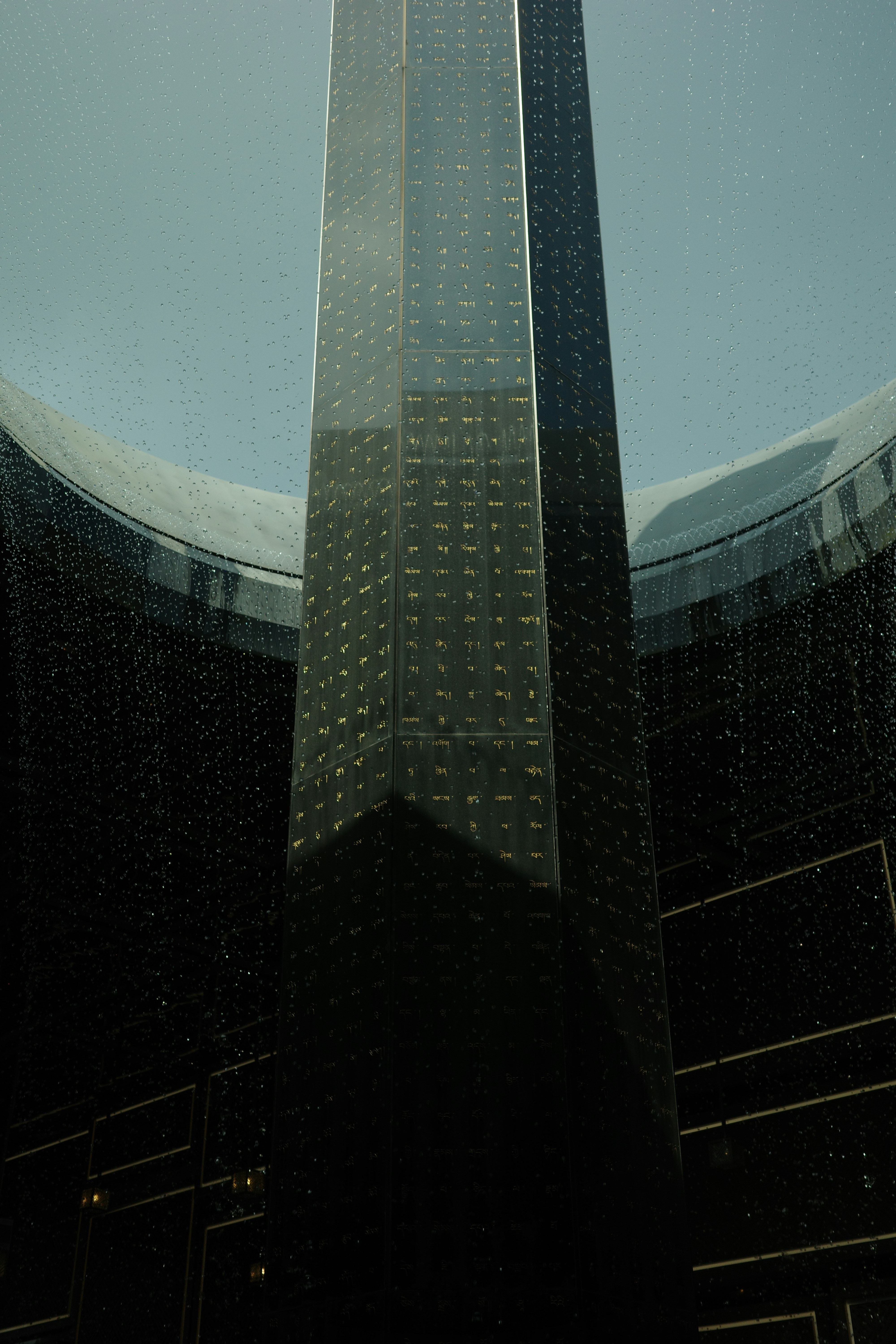Monolithic Spire Pierced by Rain: A Modern Facade of Glass and Steel