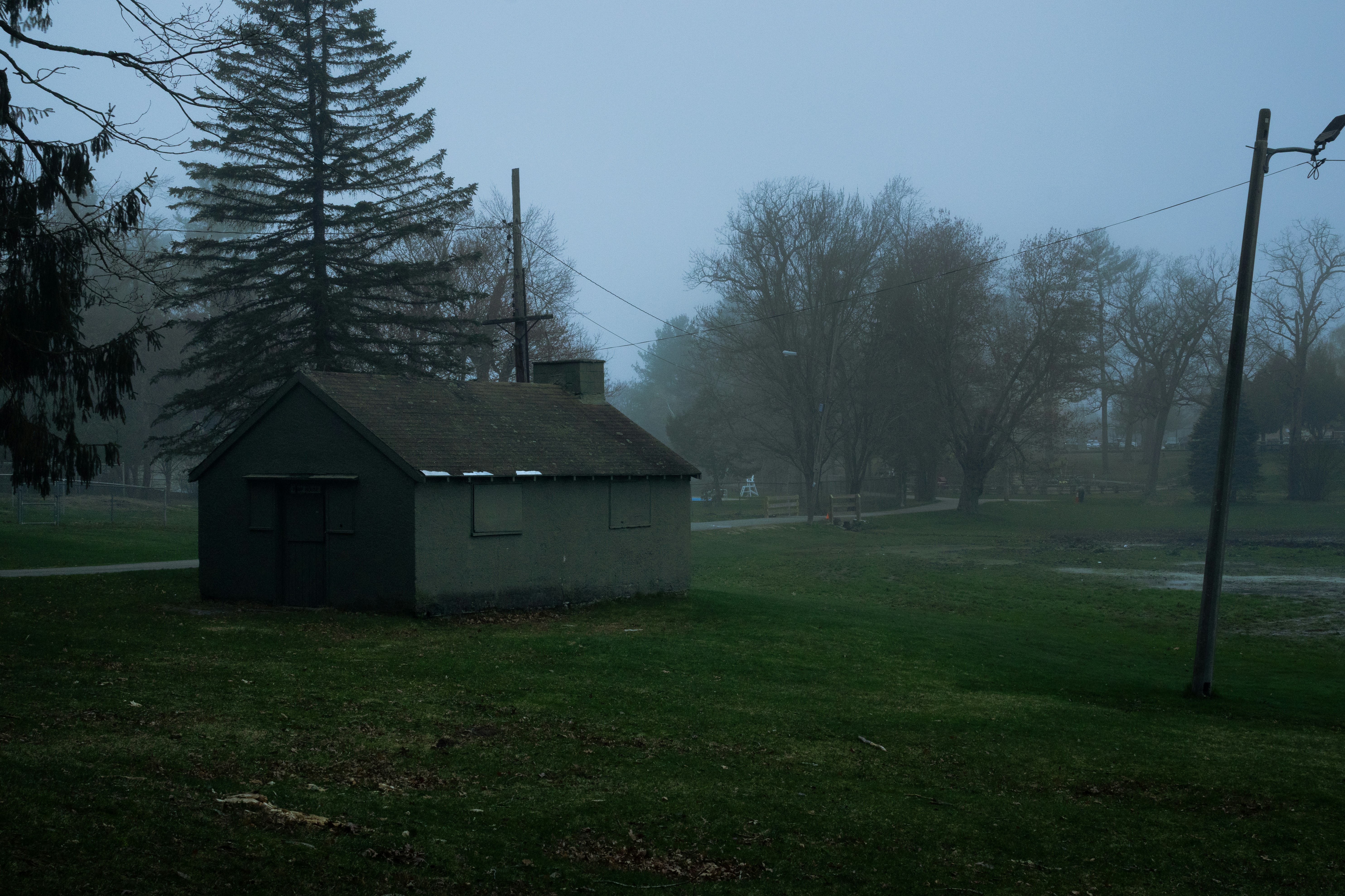 Fog over the Quiet Grounds: A Small Utility Shed in Distant Haze
