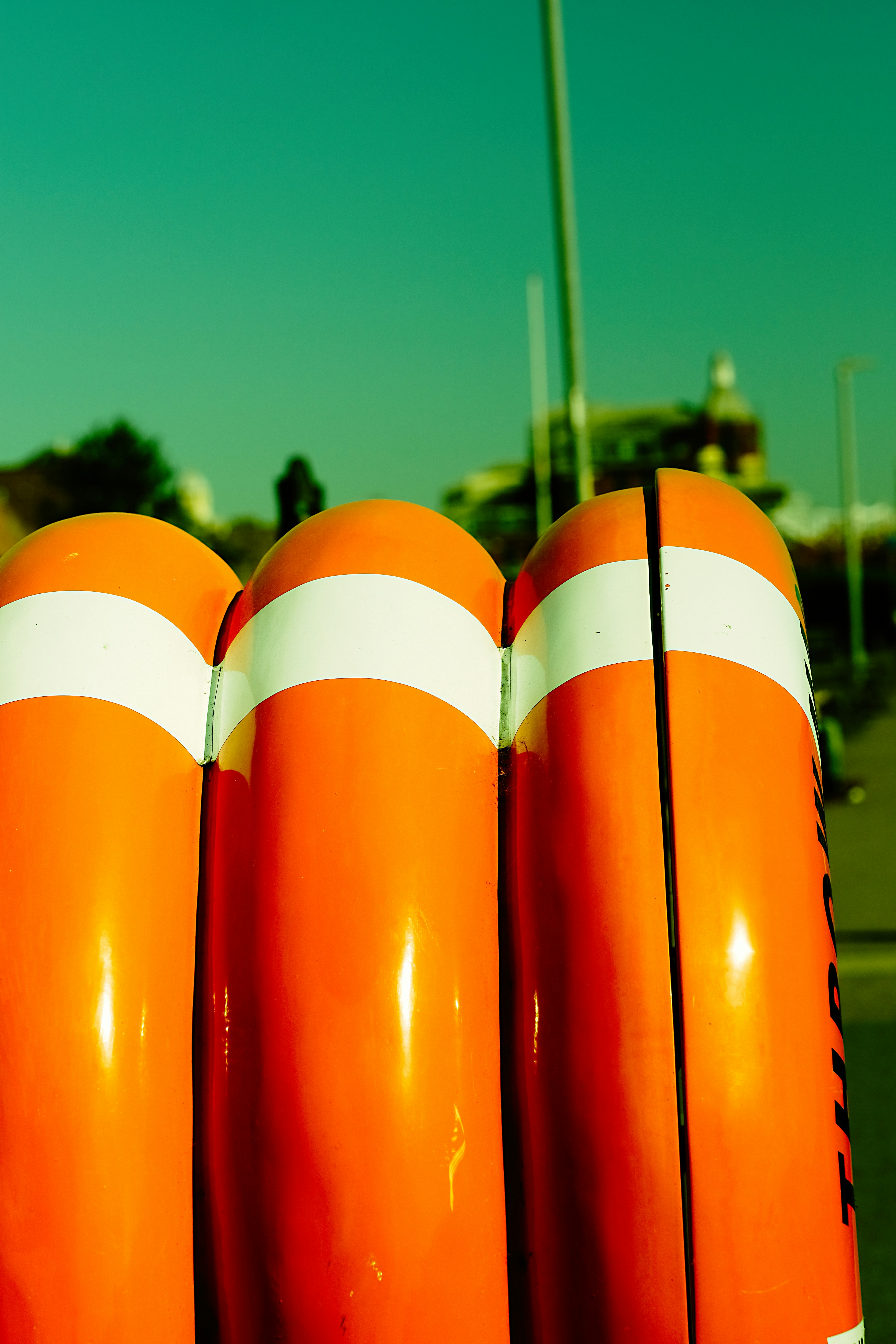 Industrial Orange Towers: A Bold Row of Safety Barrels Against a Teal Sky