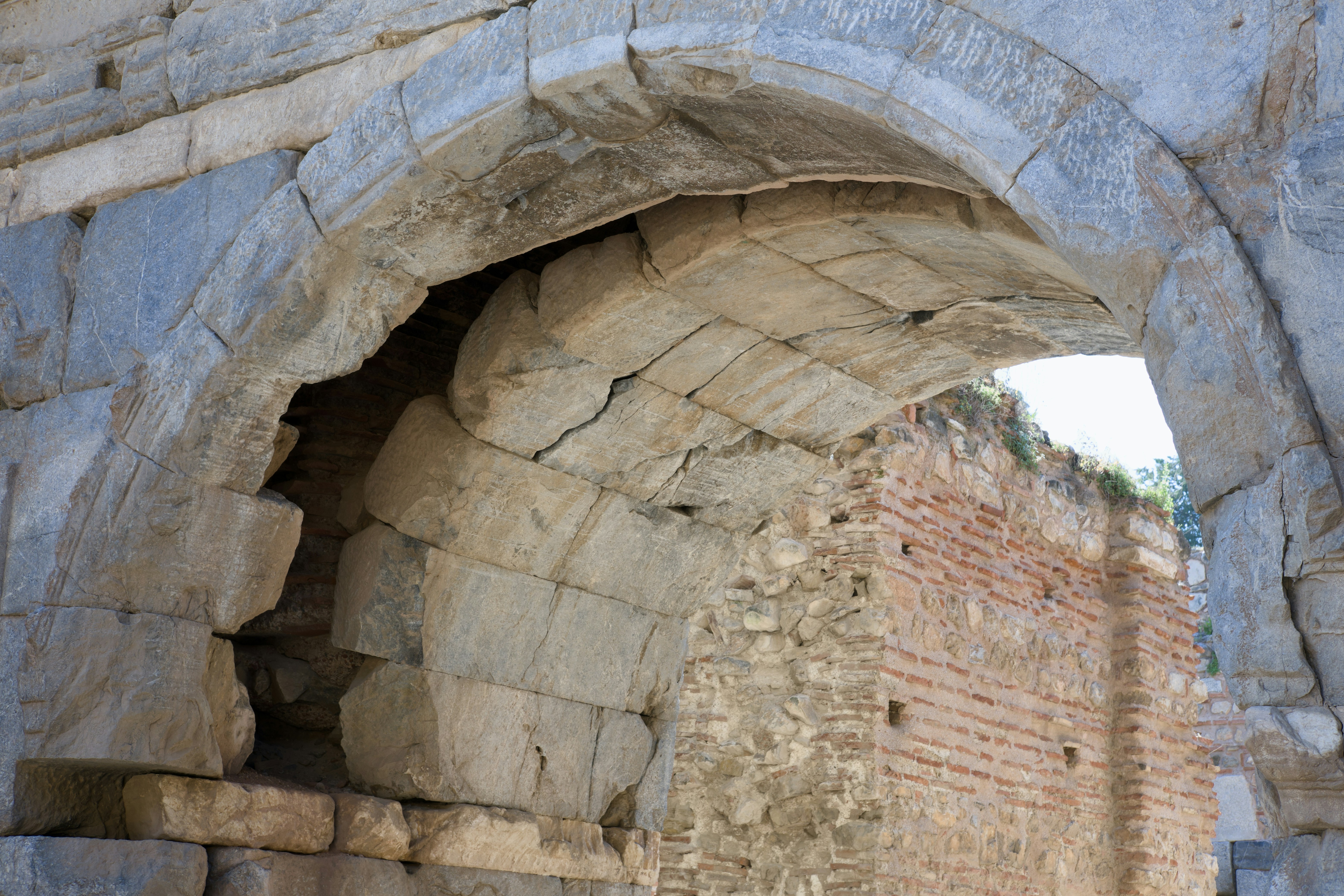 Archway of Time: A Weathered Stone Gate into Old Brickwork