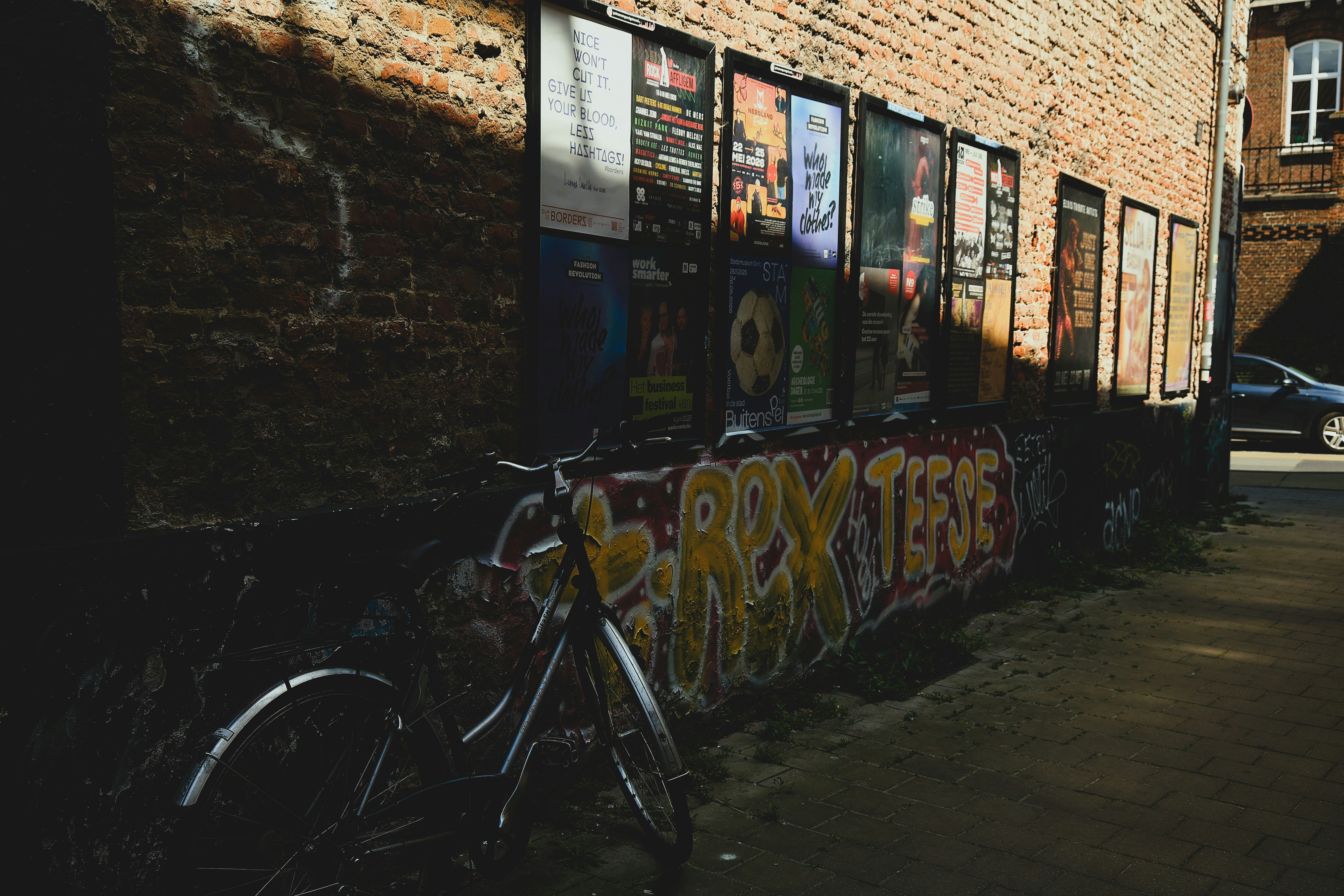 Graffiti Terrace: Bike Leaning by a Backlit Poster Wall
