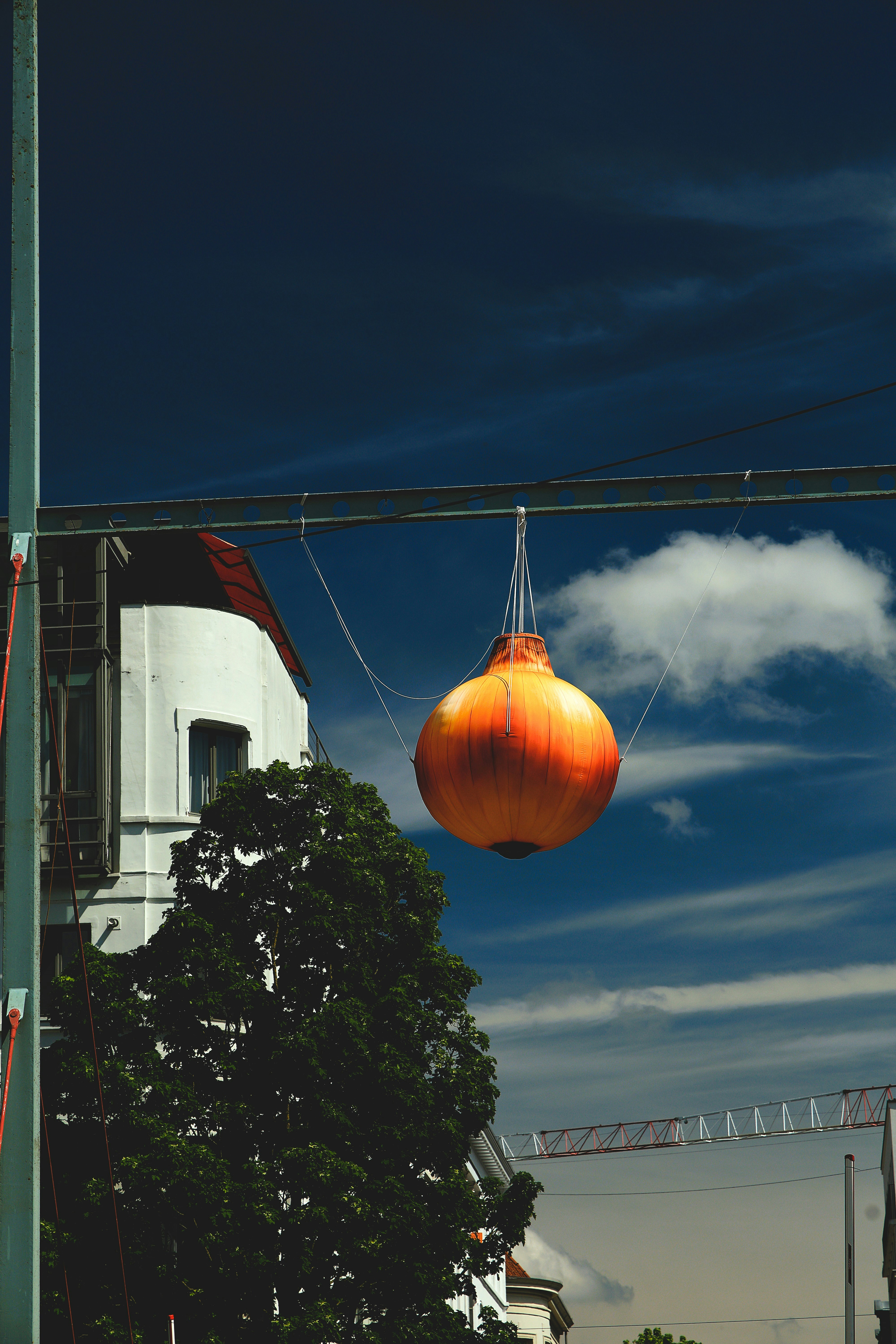 Floating Lantern Orbit: An Orange Sphere Hovering Above an Industrial Landscape
