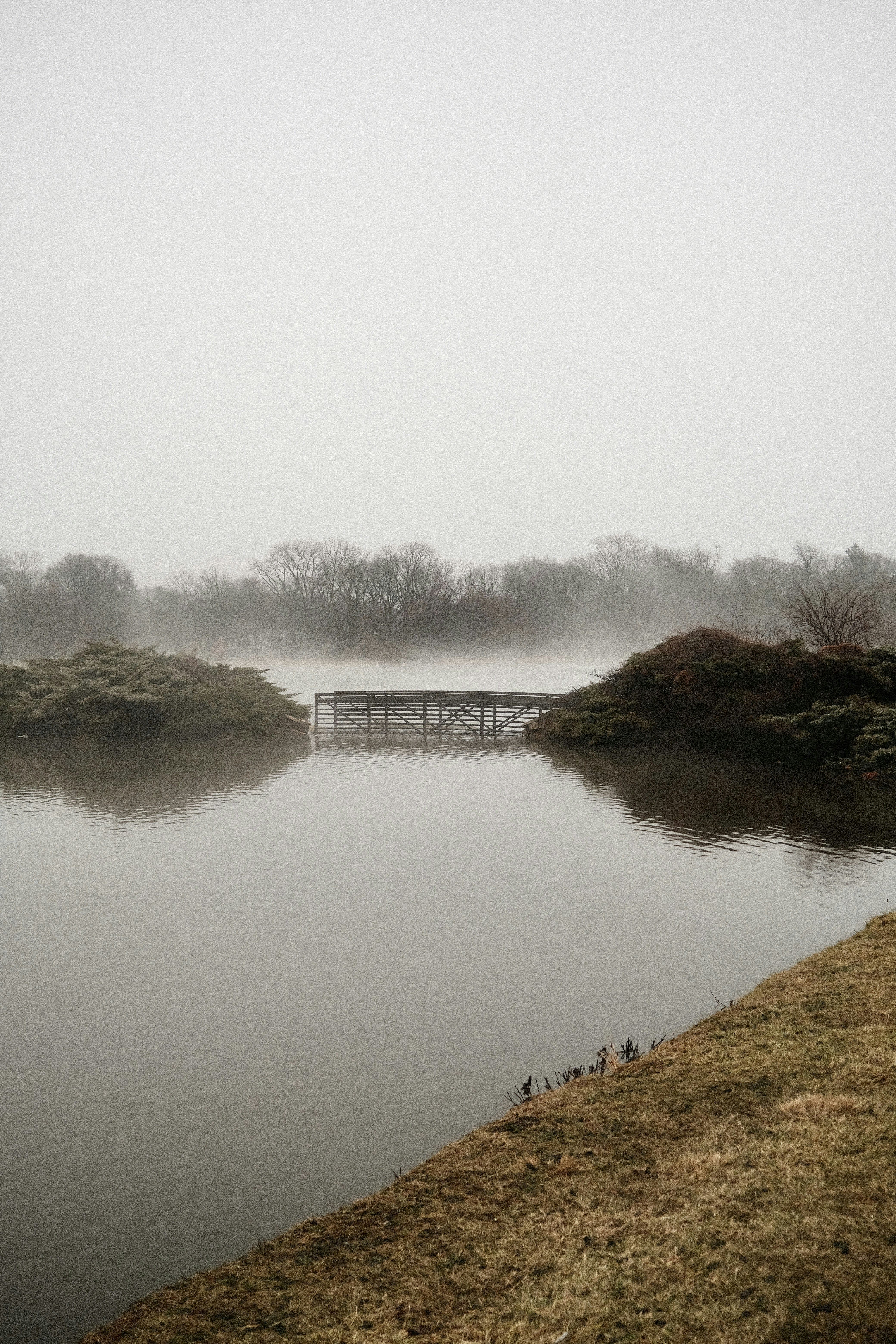 Mist over the Quiet Lake with a Wooden Bridge