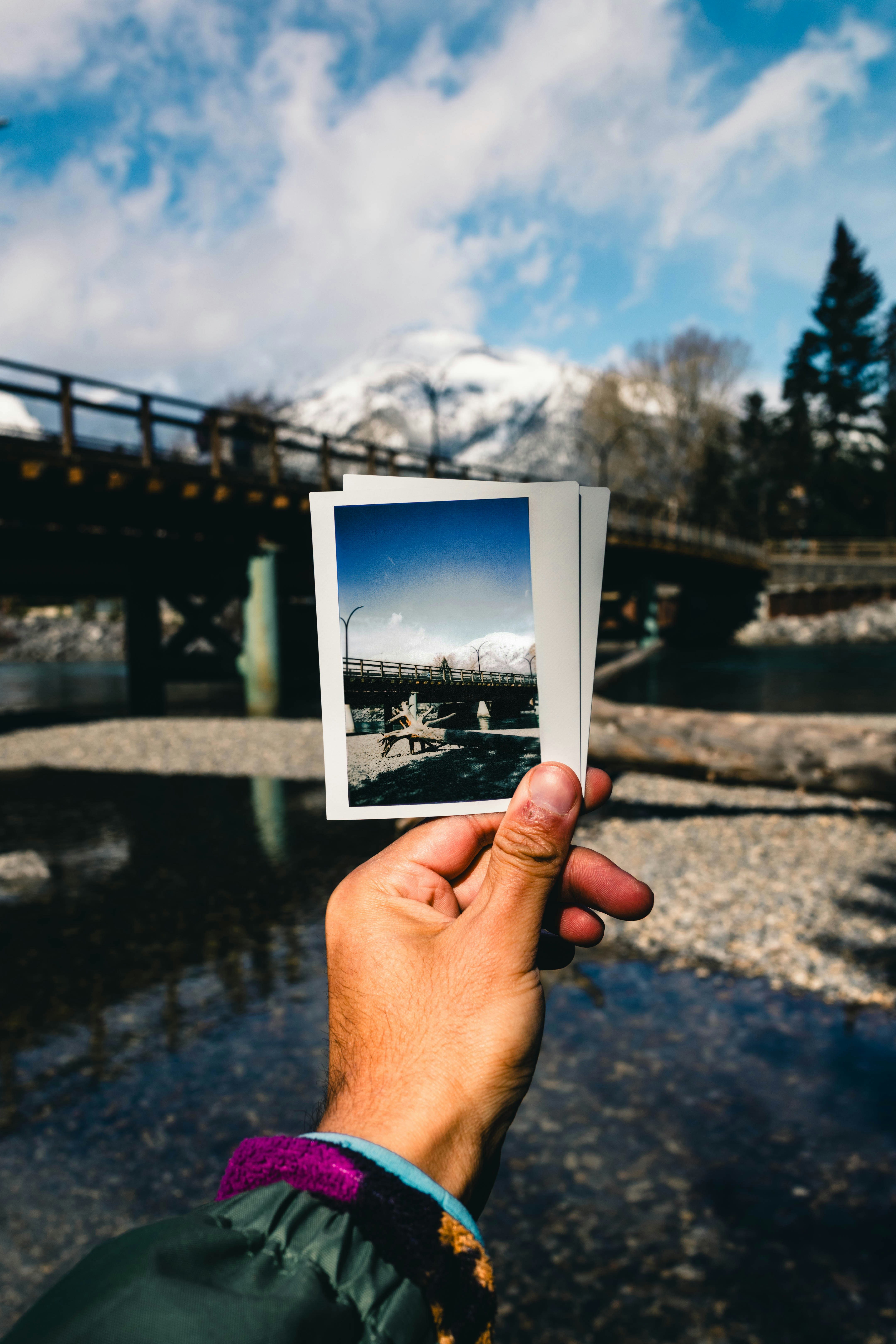 Handful of Memories: A Polaroid Portrait Against a Mountain Bridge