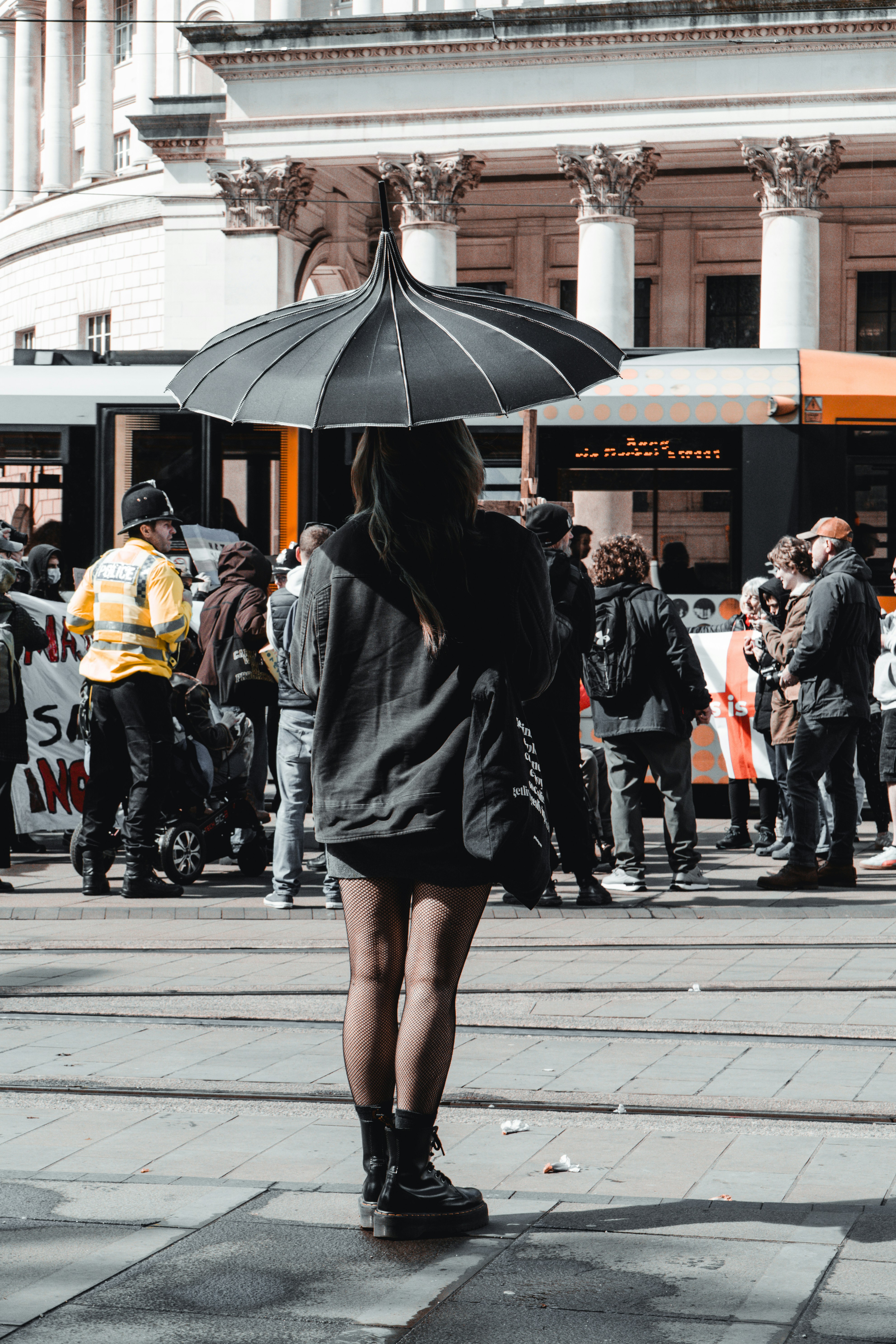 Umbrella of Stillness: A lone figure facing a bustling city street