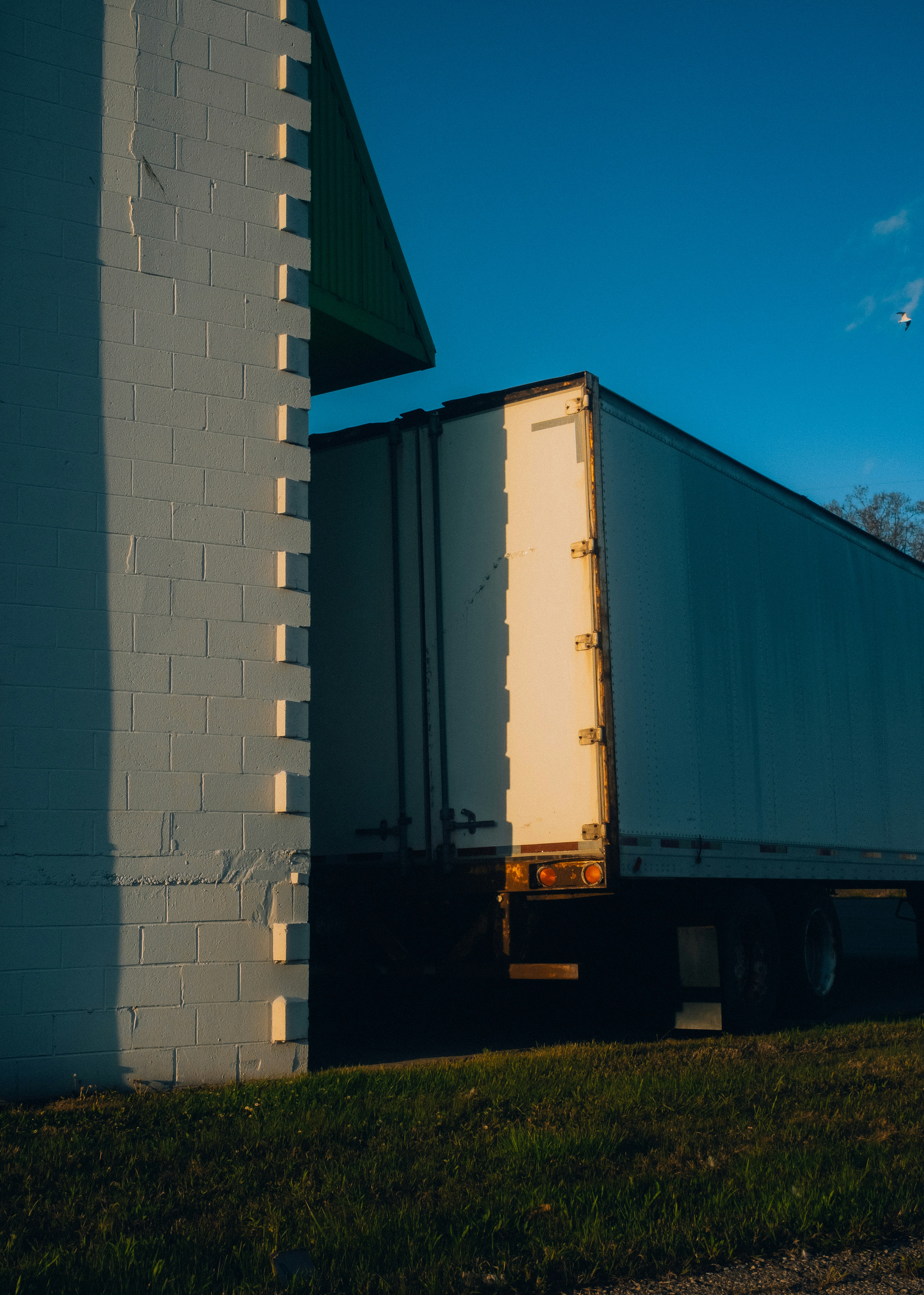 Dockside Shadow: A Trailer Against a Warehouse Wall