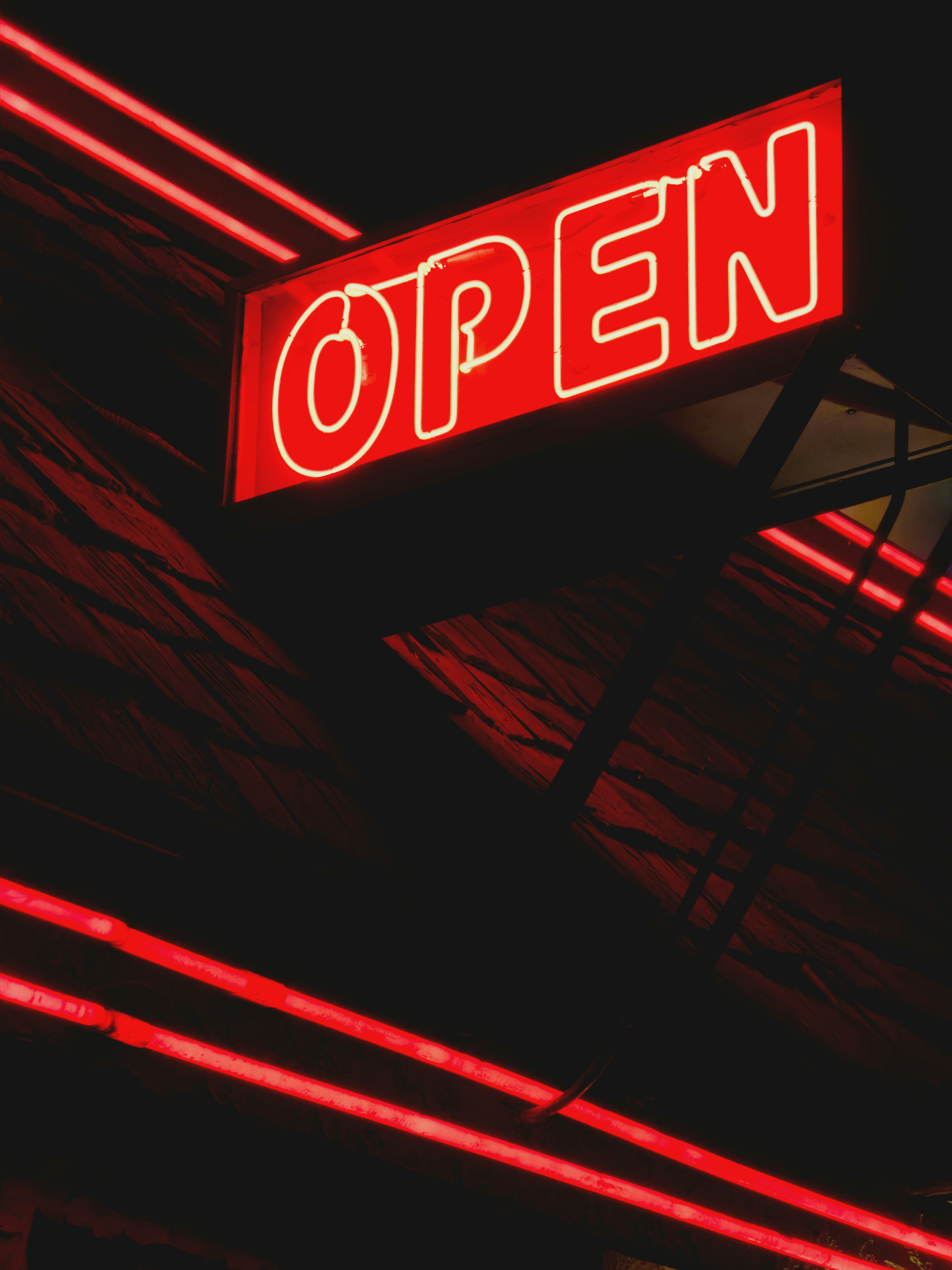 Neon Open Sign Casting Red Glare Over A Brick Facade