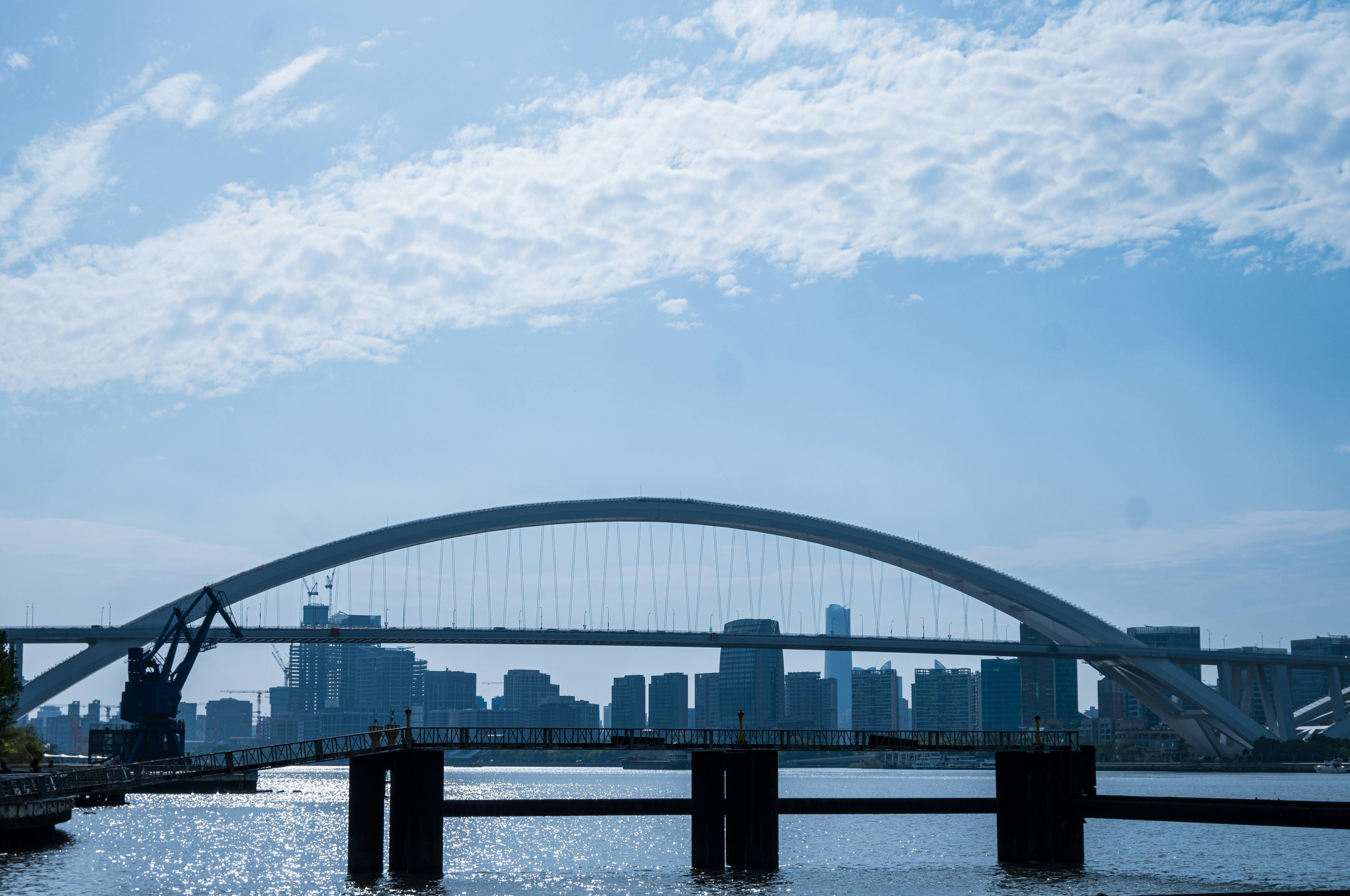Mirrored Arc: A City Bridge Silhouette Over Calm Waters