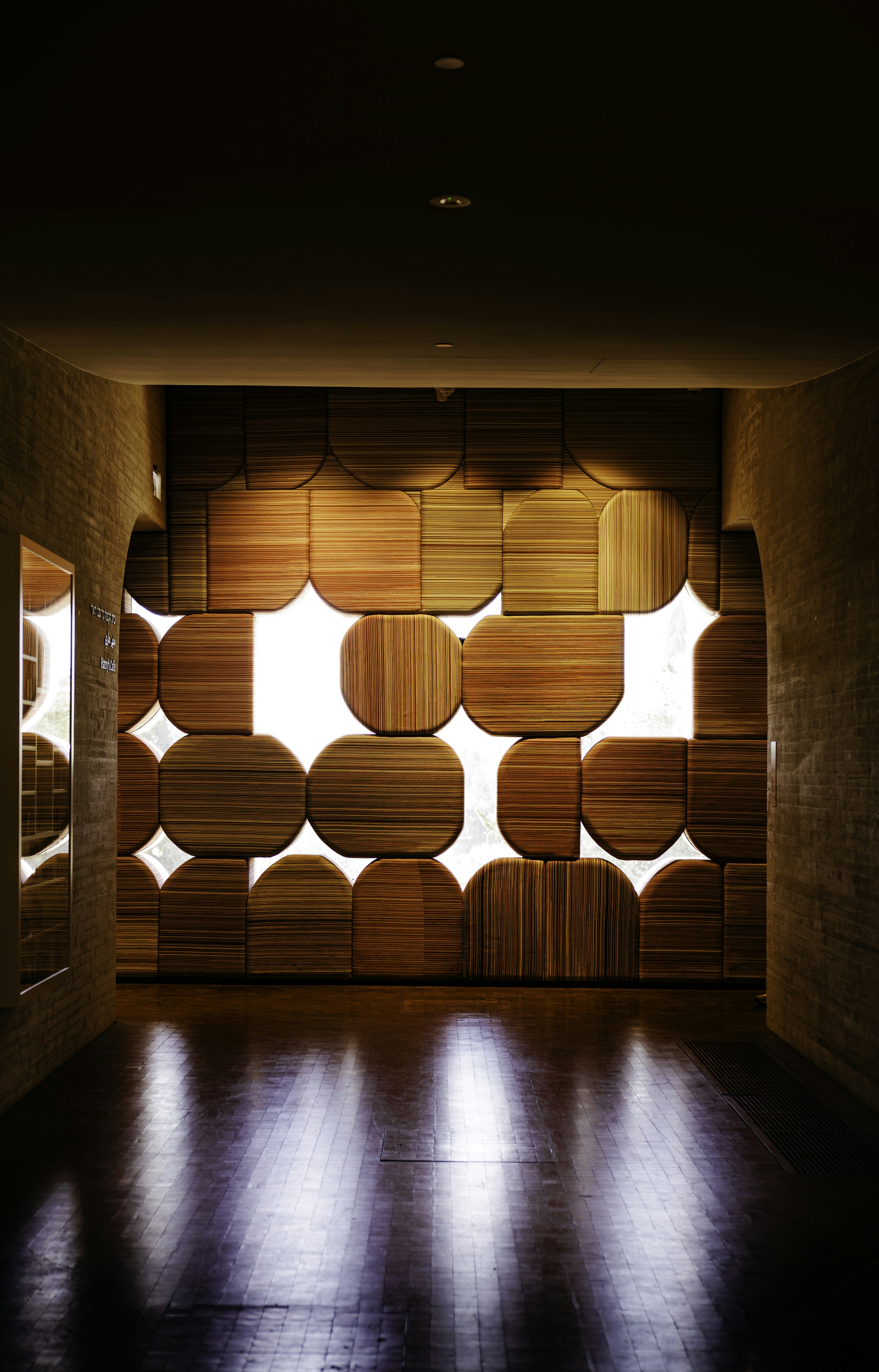 Bright Grid of Wooden Circles Illuminates a Narrow Gallery
