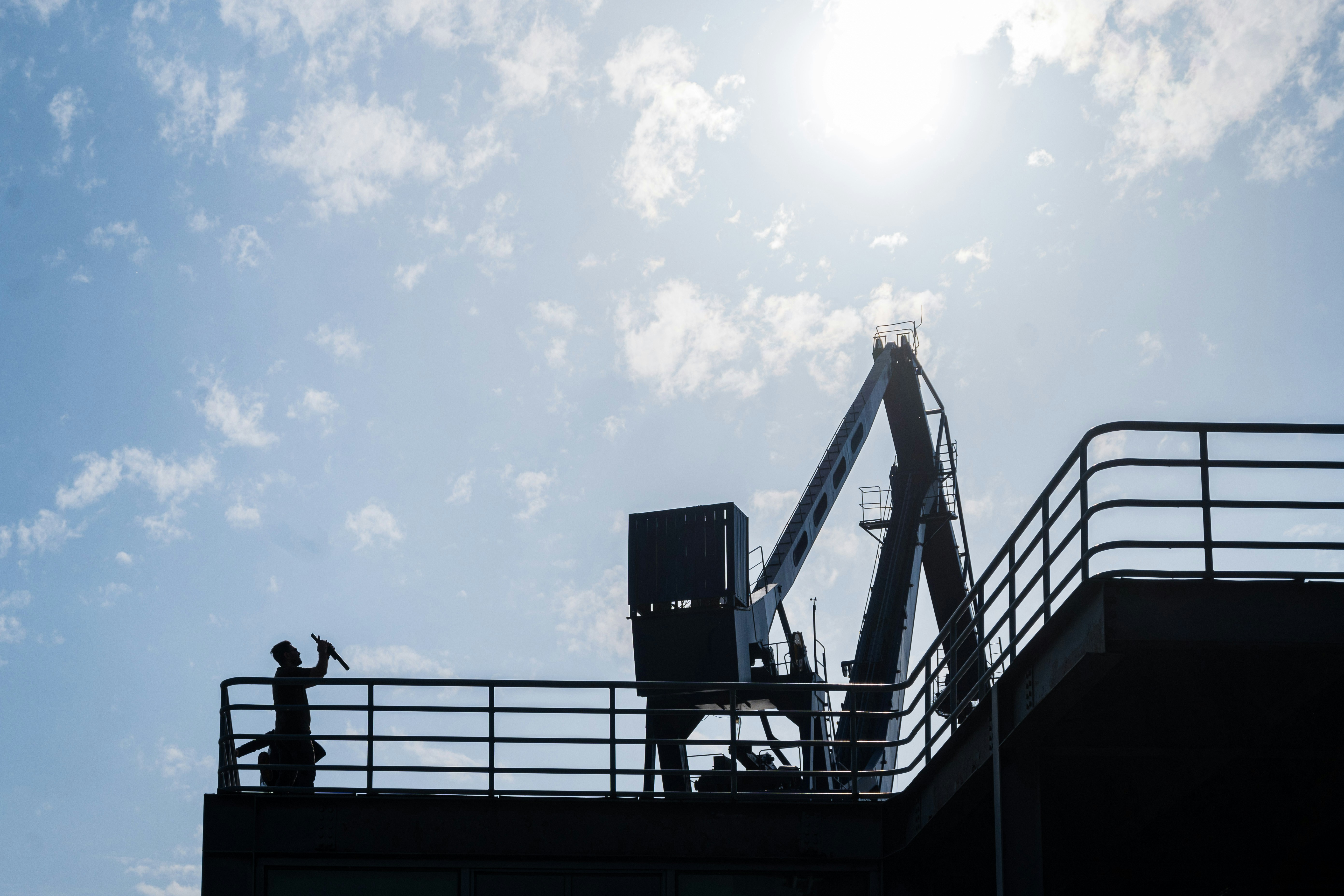Silhouette at the Skyline: A Crane and Rail Balcony at Dusk