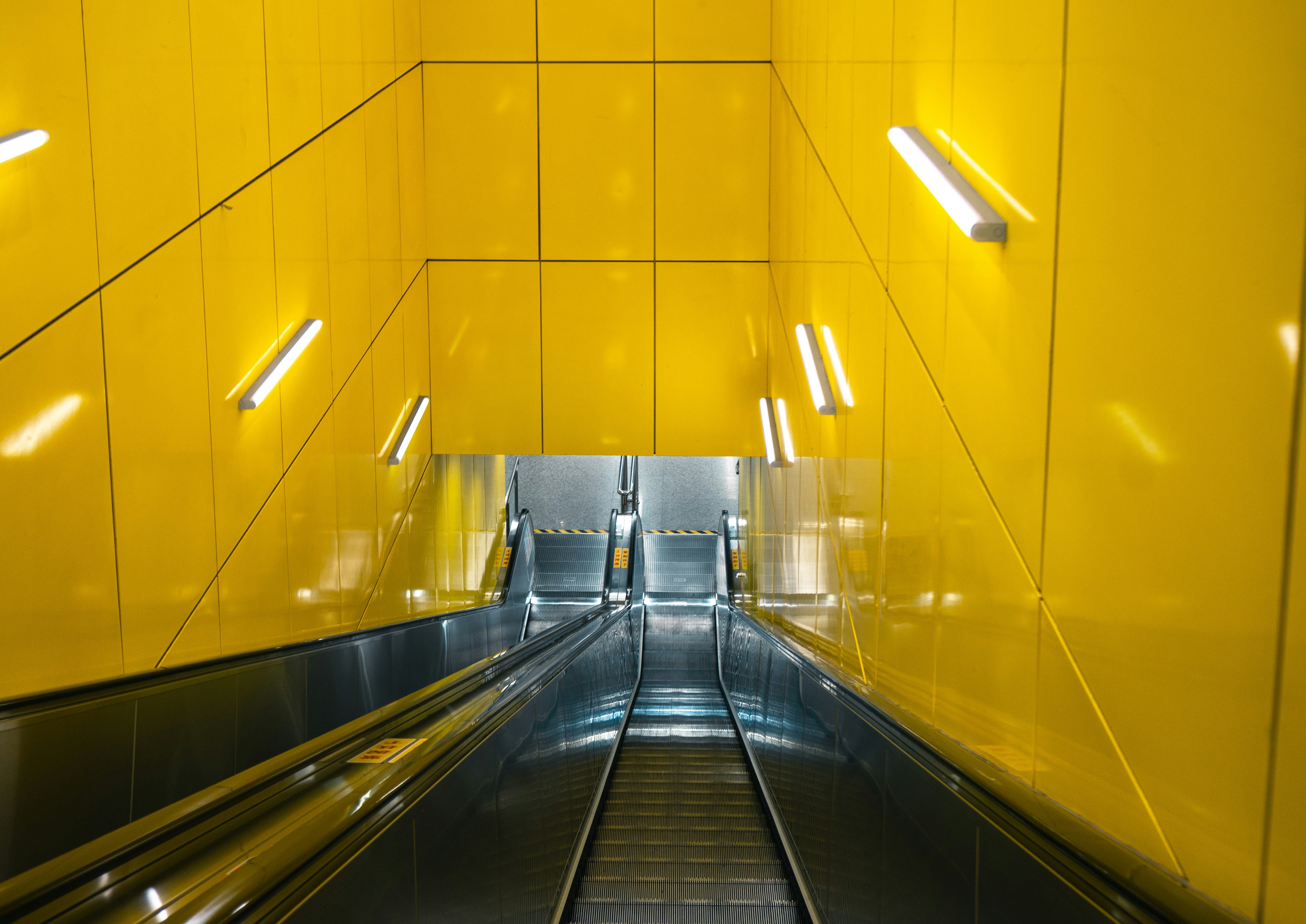 Yellow Tunnel Descent: Neon Lines Toward the Escalator