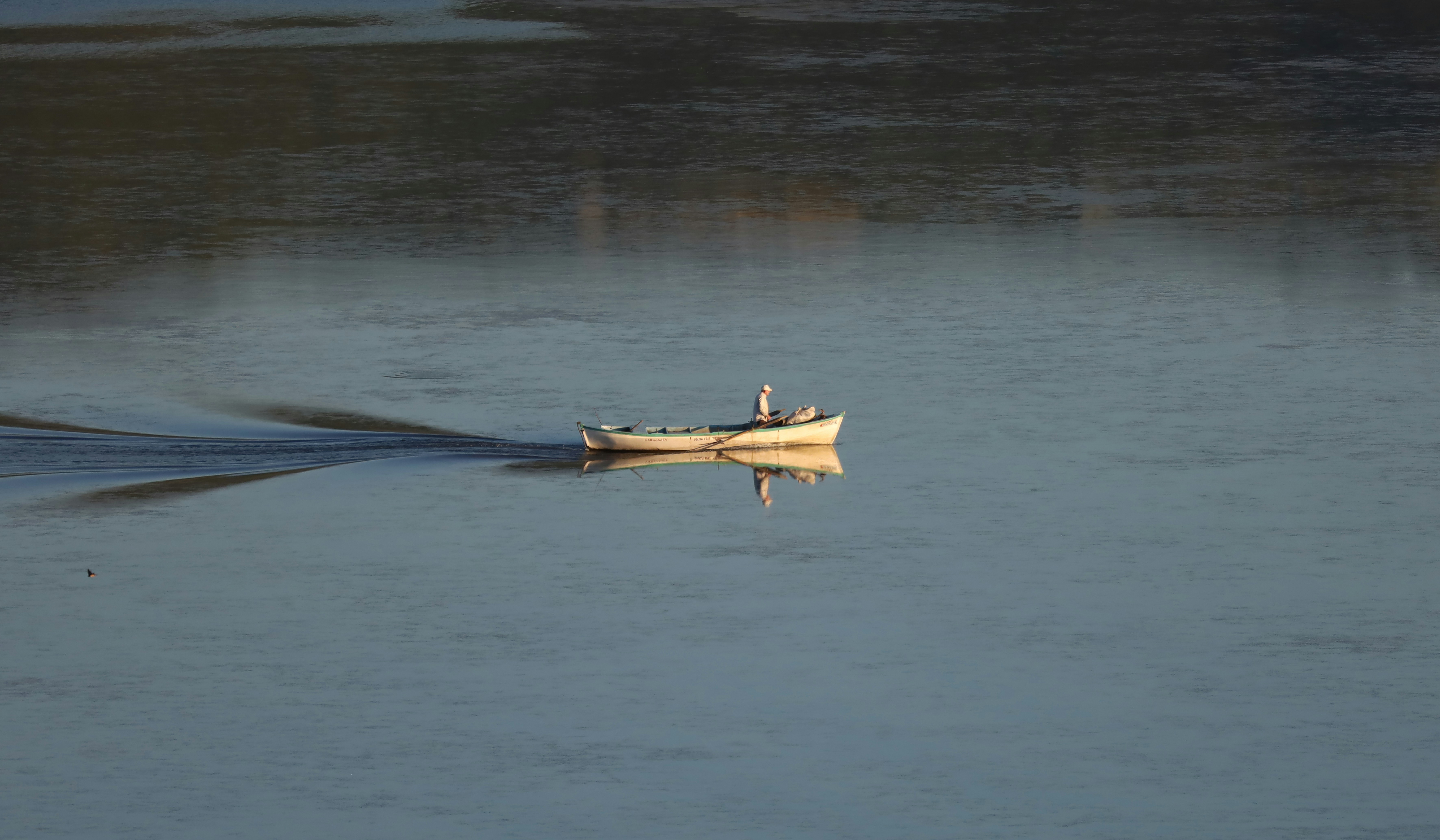Silent Row: a lone canoe gliding across a glassy lake at dusk
